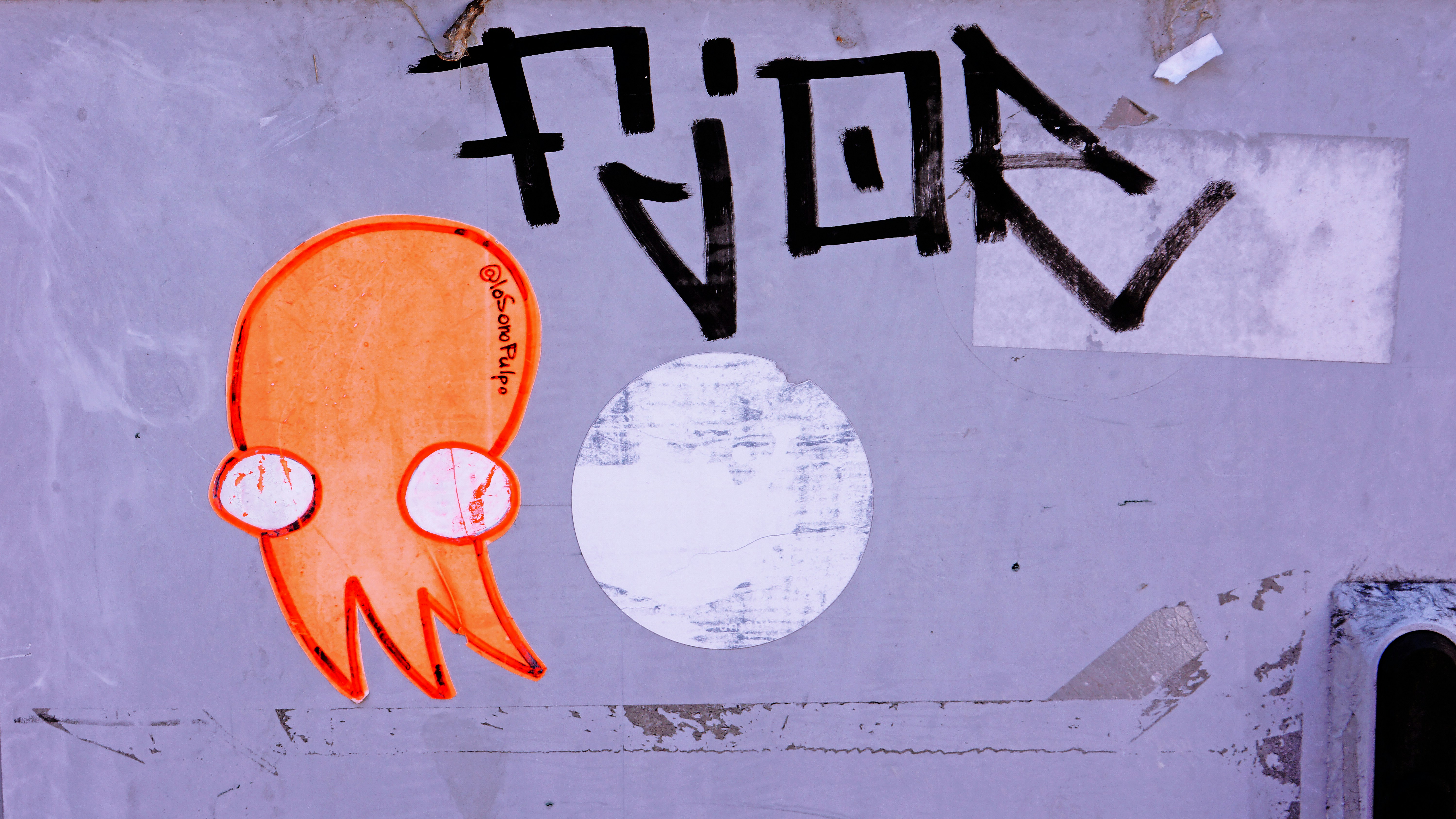 Orange Squid Graffiti Beside a Pale Moon on a Weathered Wall