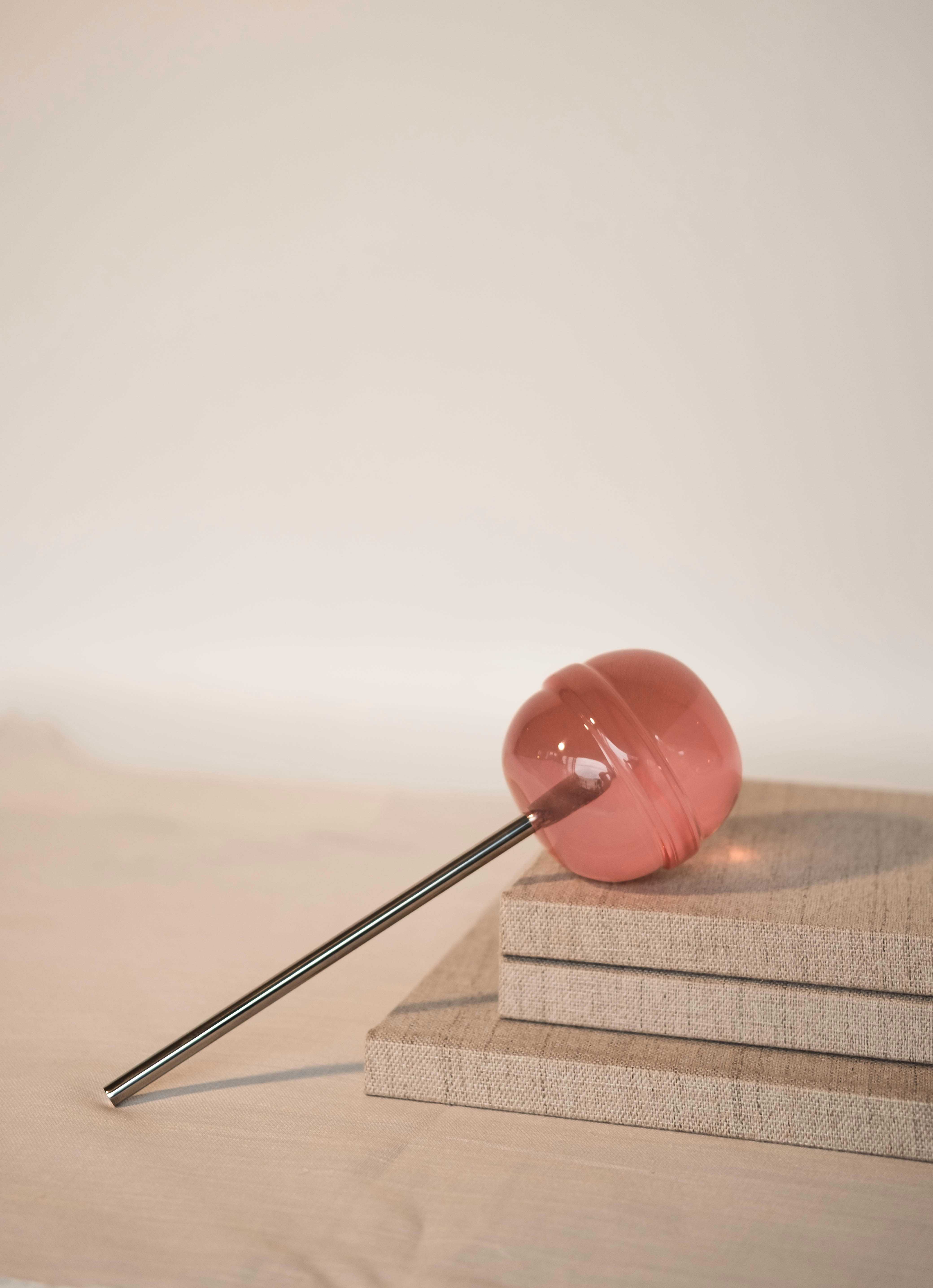 A pink lollipop rests on a stack of books.