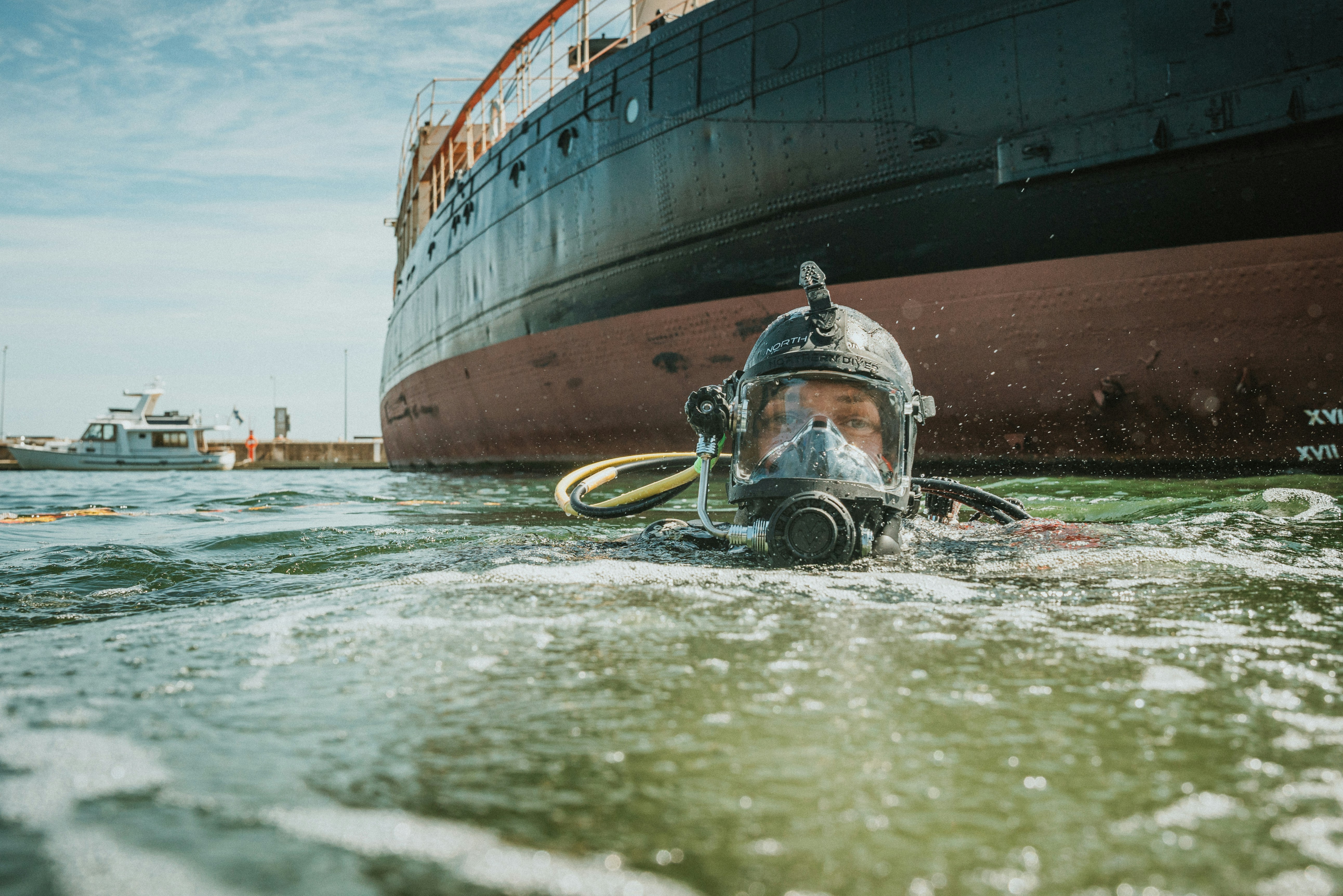 A diver surfaces near a large ship.