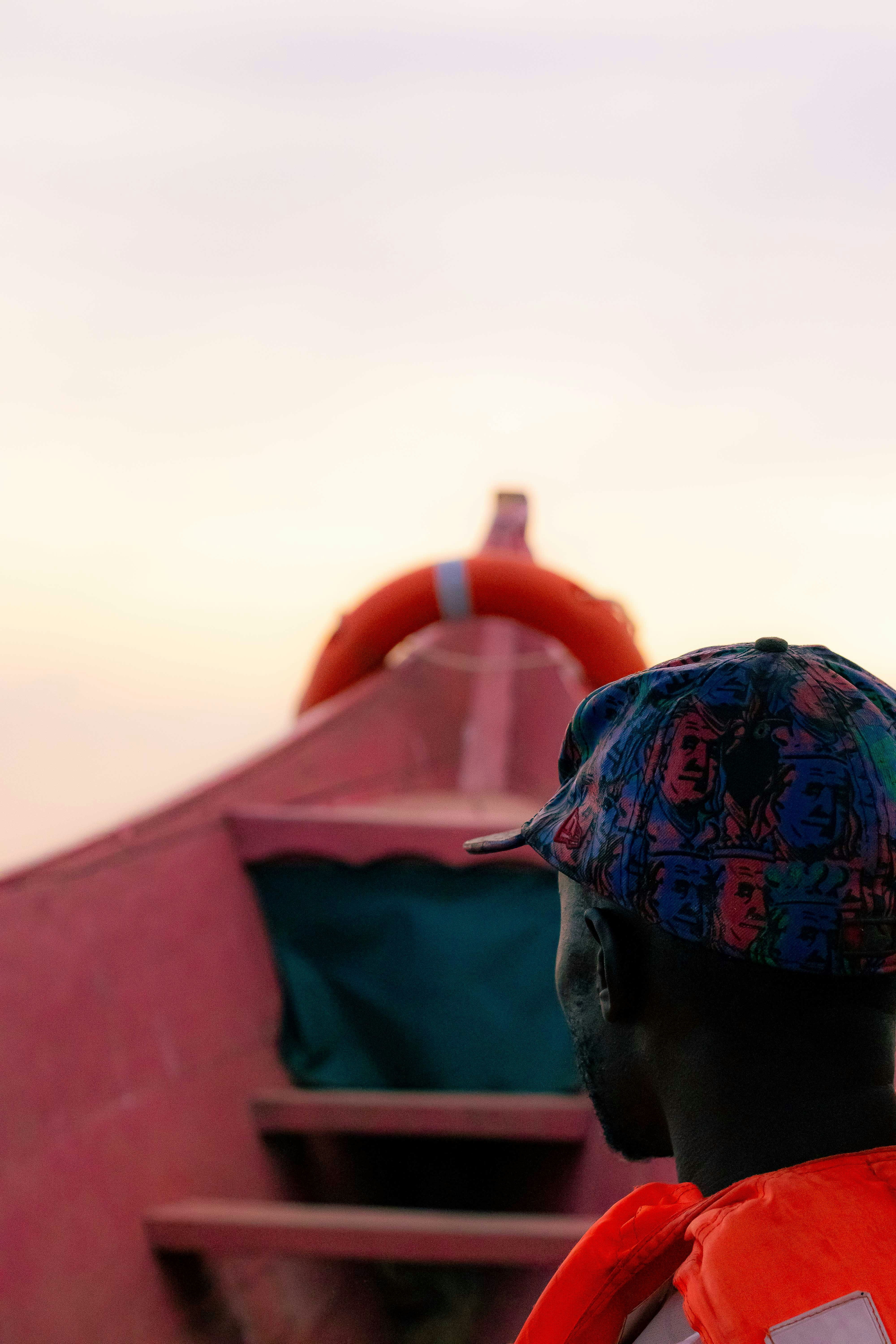 Dusk on the Deck: Back View of a Colorful Cap Beside a Pink Boat