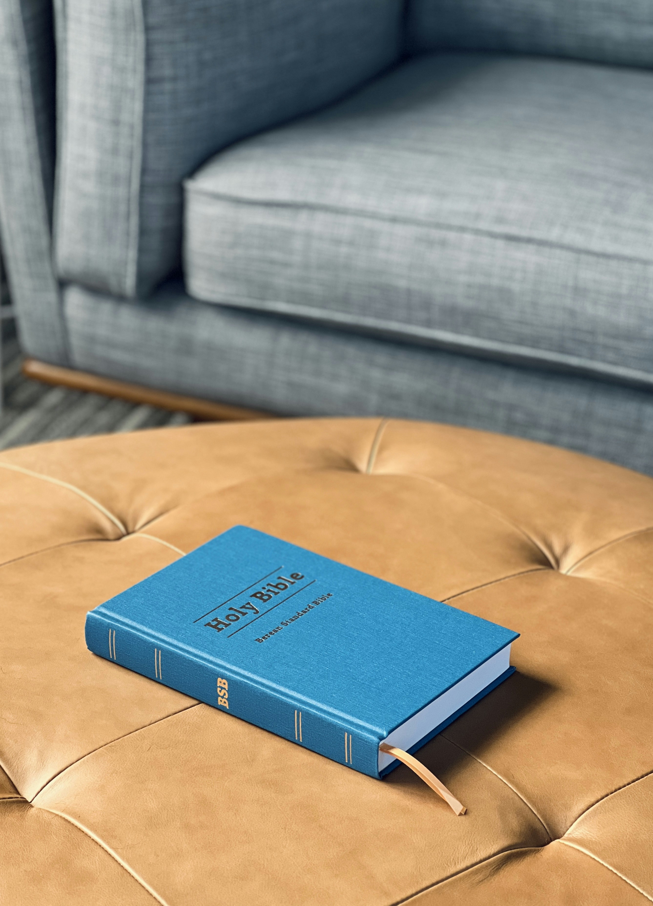 A Quiet Reflection: The Blue Bible on a Cozy Ottoman