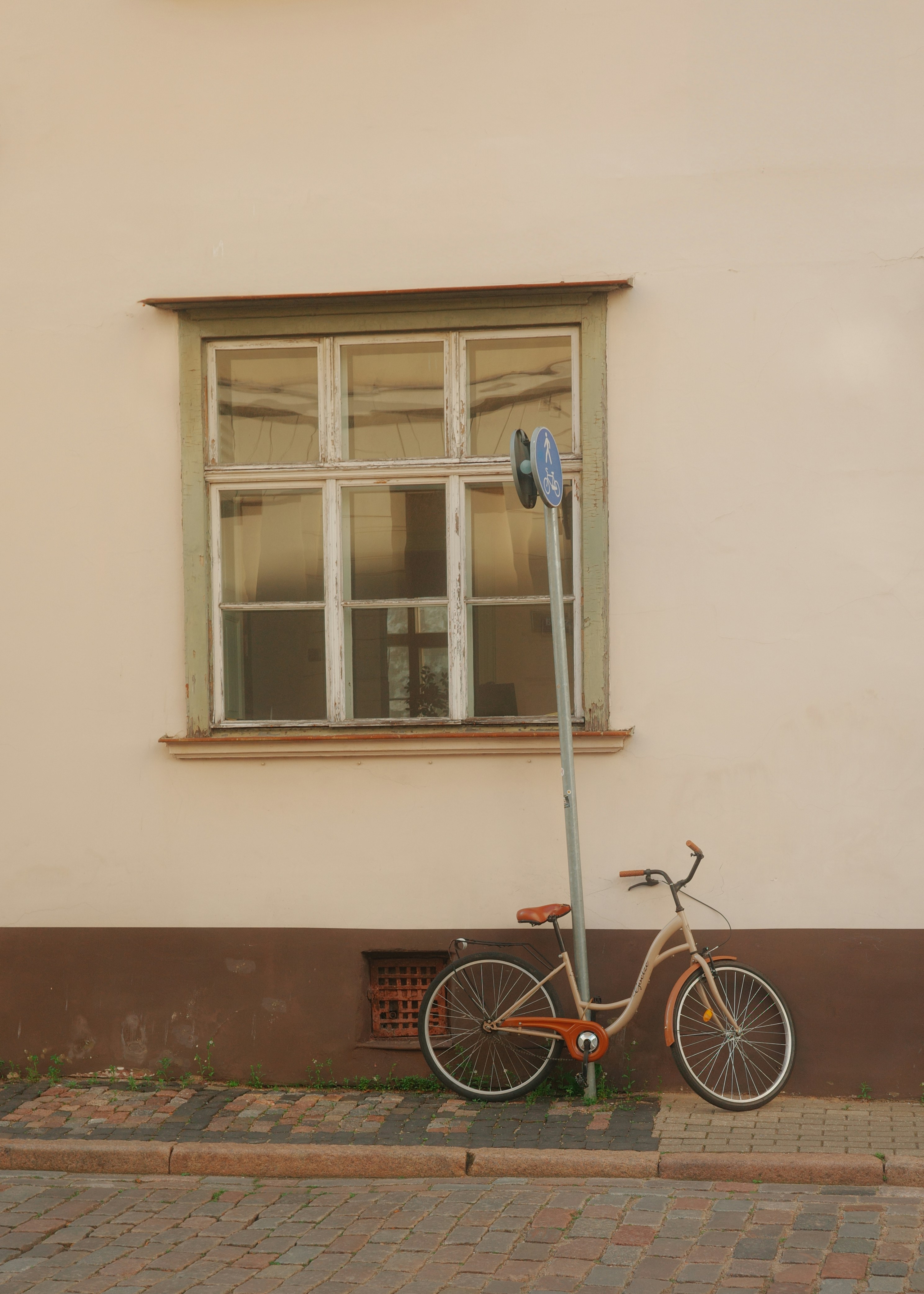 A vintage bicycle stands beside a traffic sign against a textured wall, evoking a sense of quiet urban life.