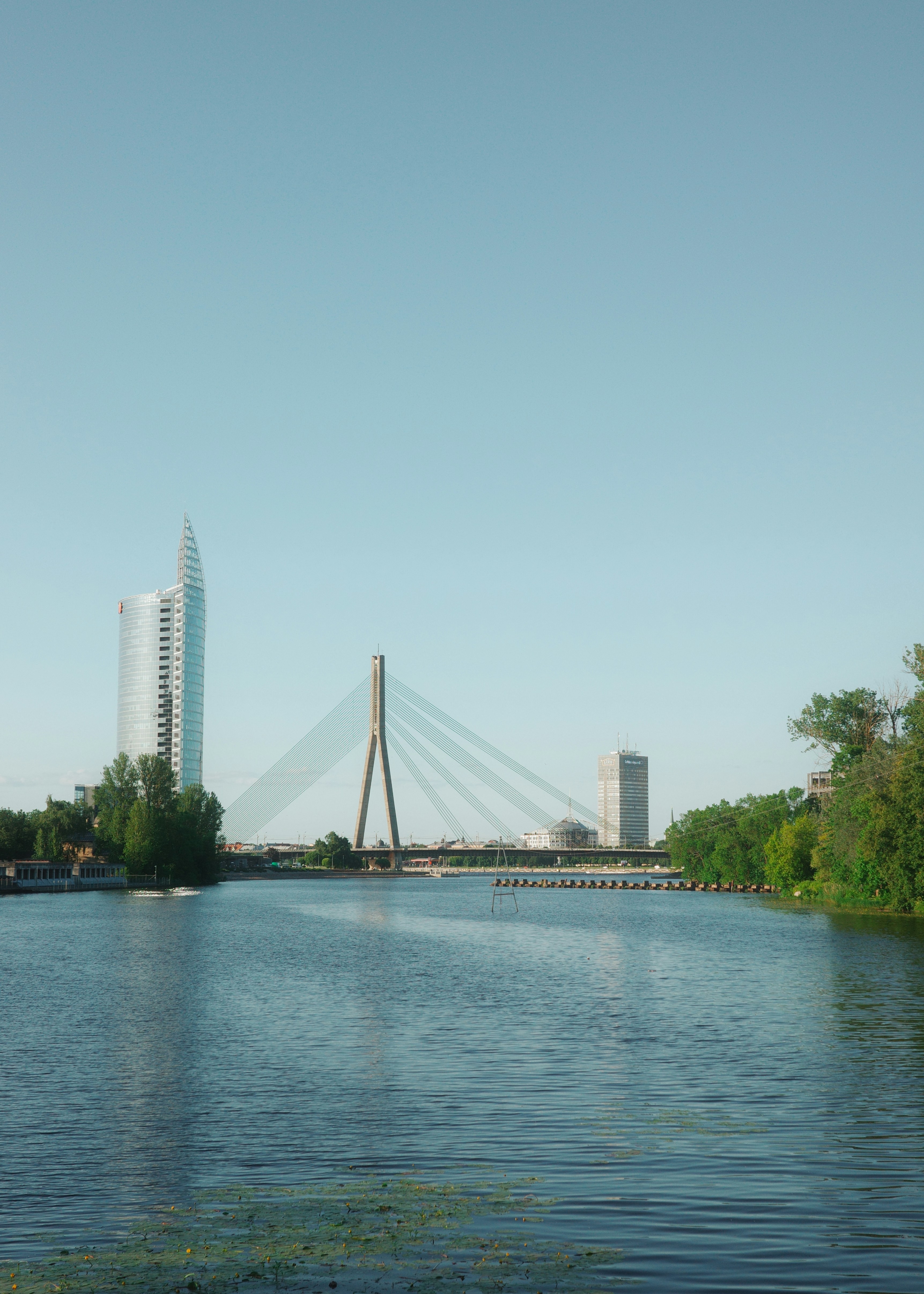 A bridge spans a river with city buildings.