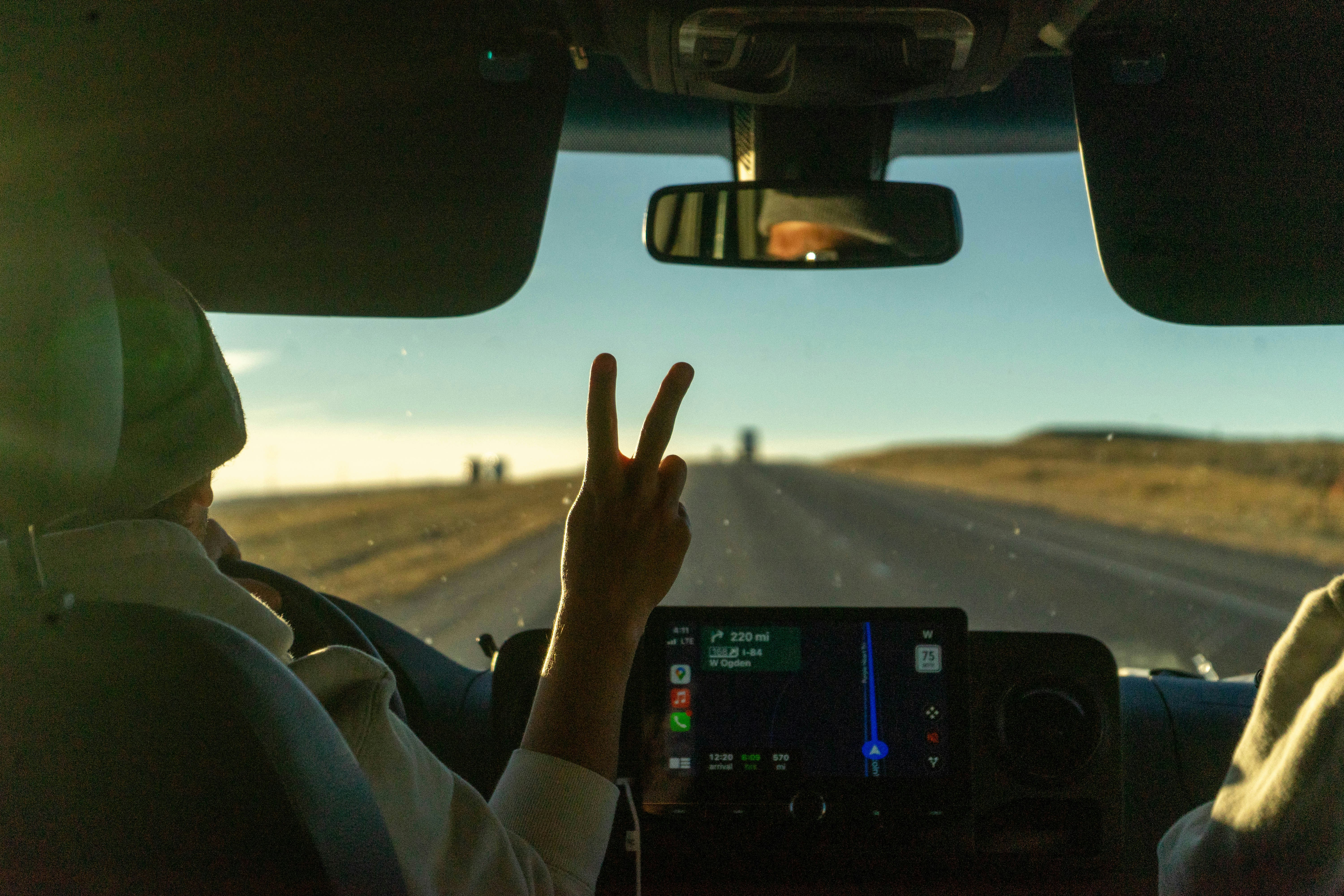 A driver shows a peace sign on the open road. photo – Free Car Image on ...