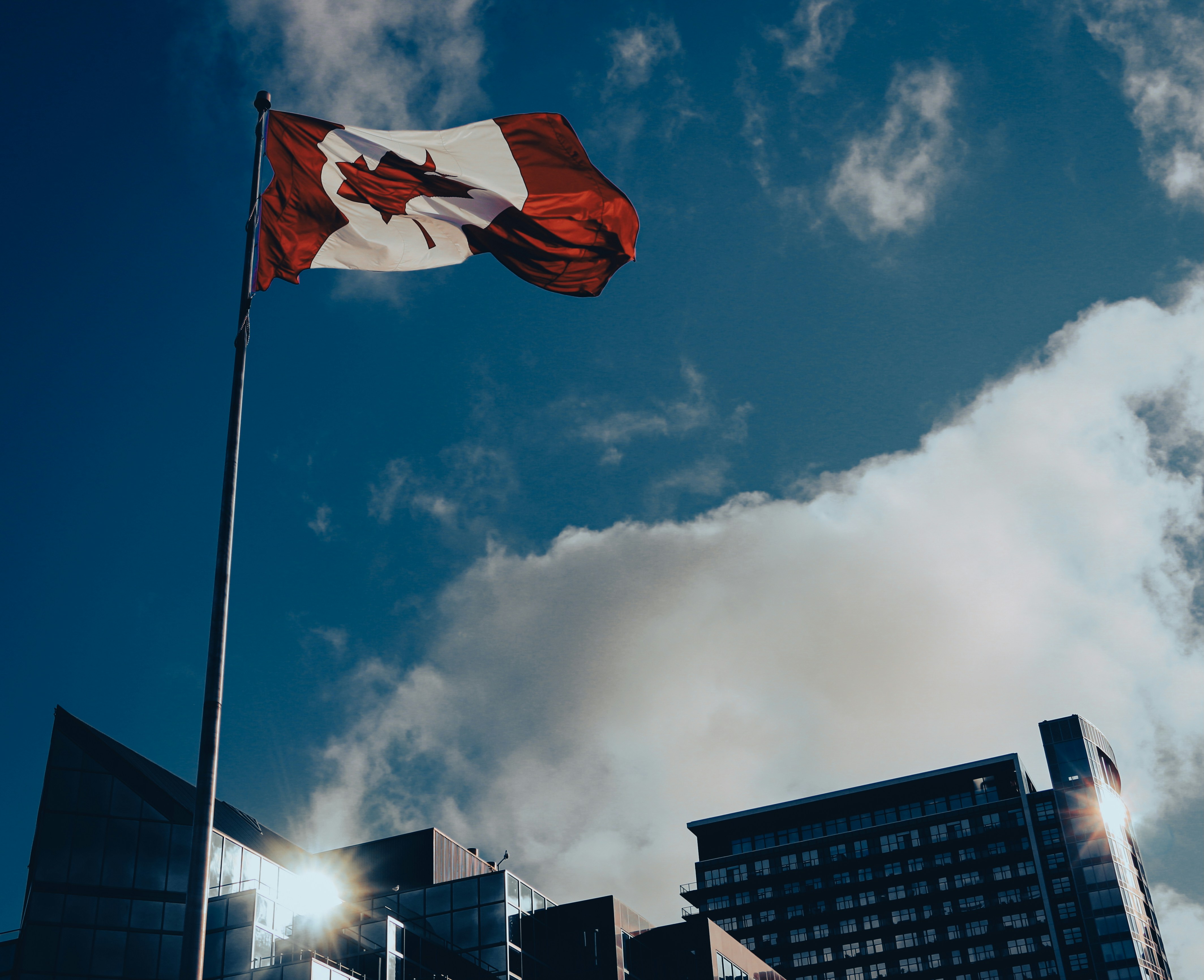 Flag Over the Glass City Skyline Beneath a Bold, Blue Sky