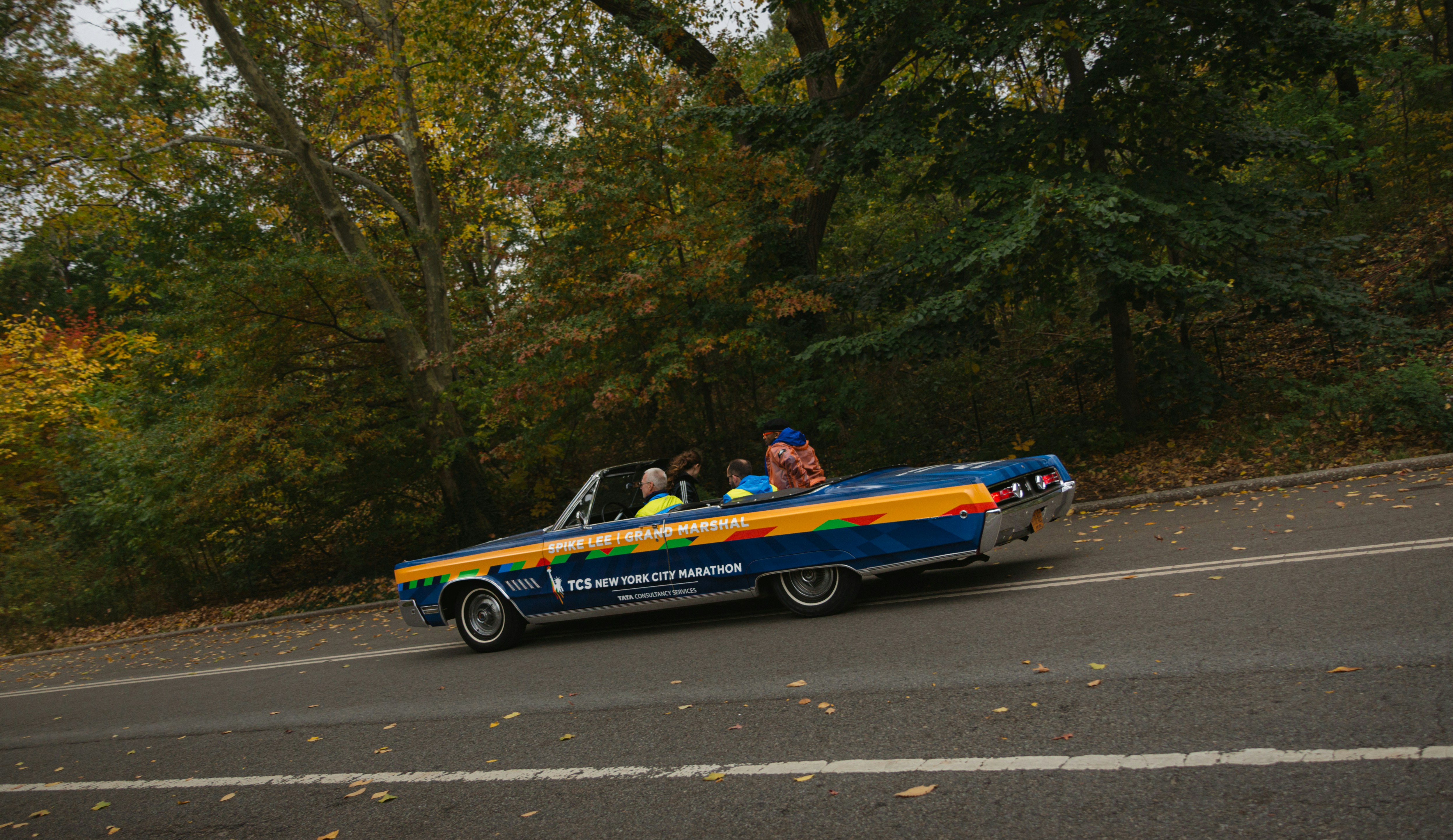 Boat-on-wheels in autumn: a retro speedboat cruiser gliding along a leaf-strewn road