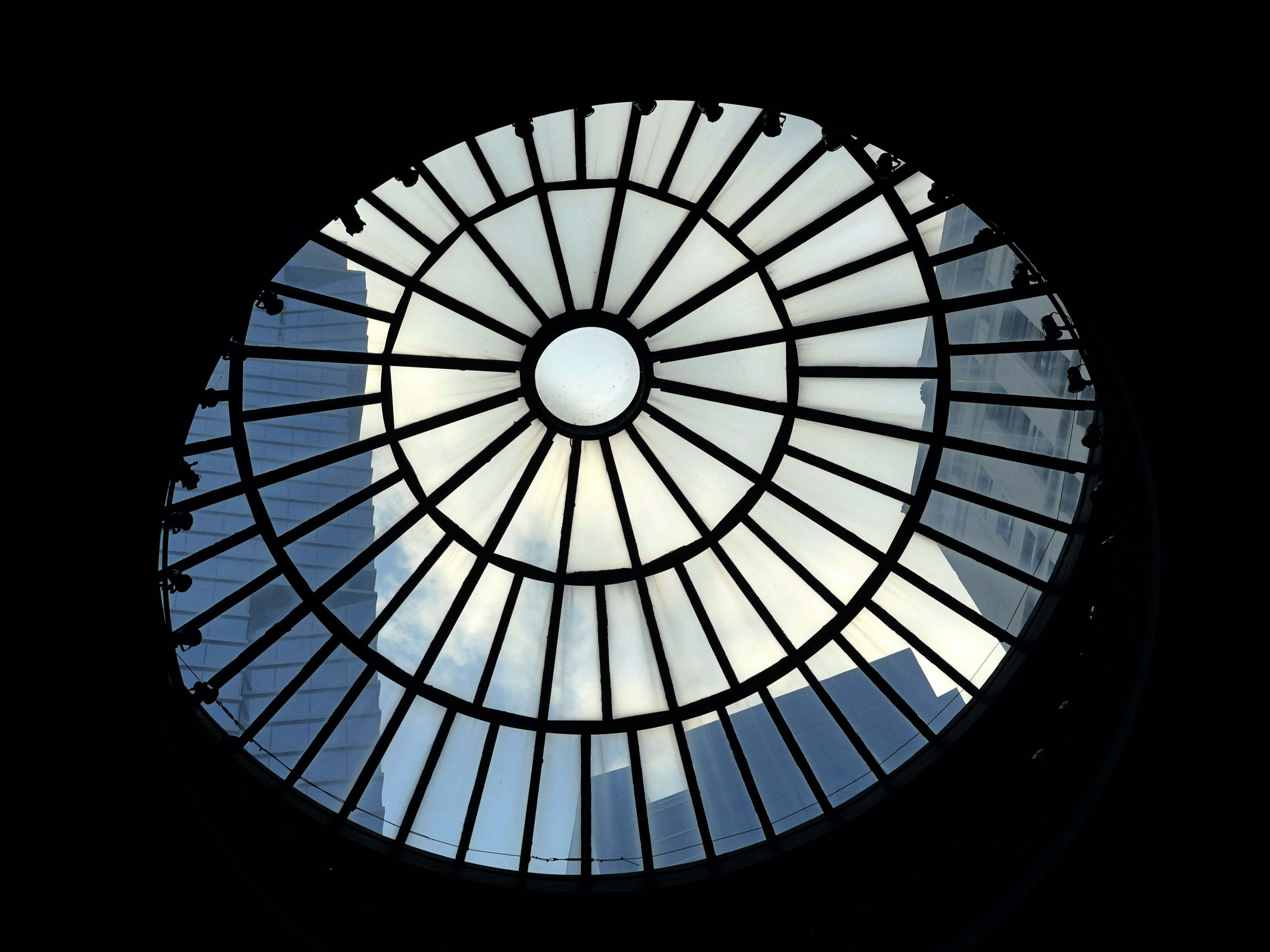 Office building high rises as seen through a skylight | A glass skylight reflects a city's sky.