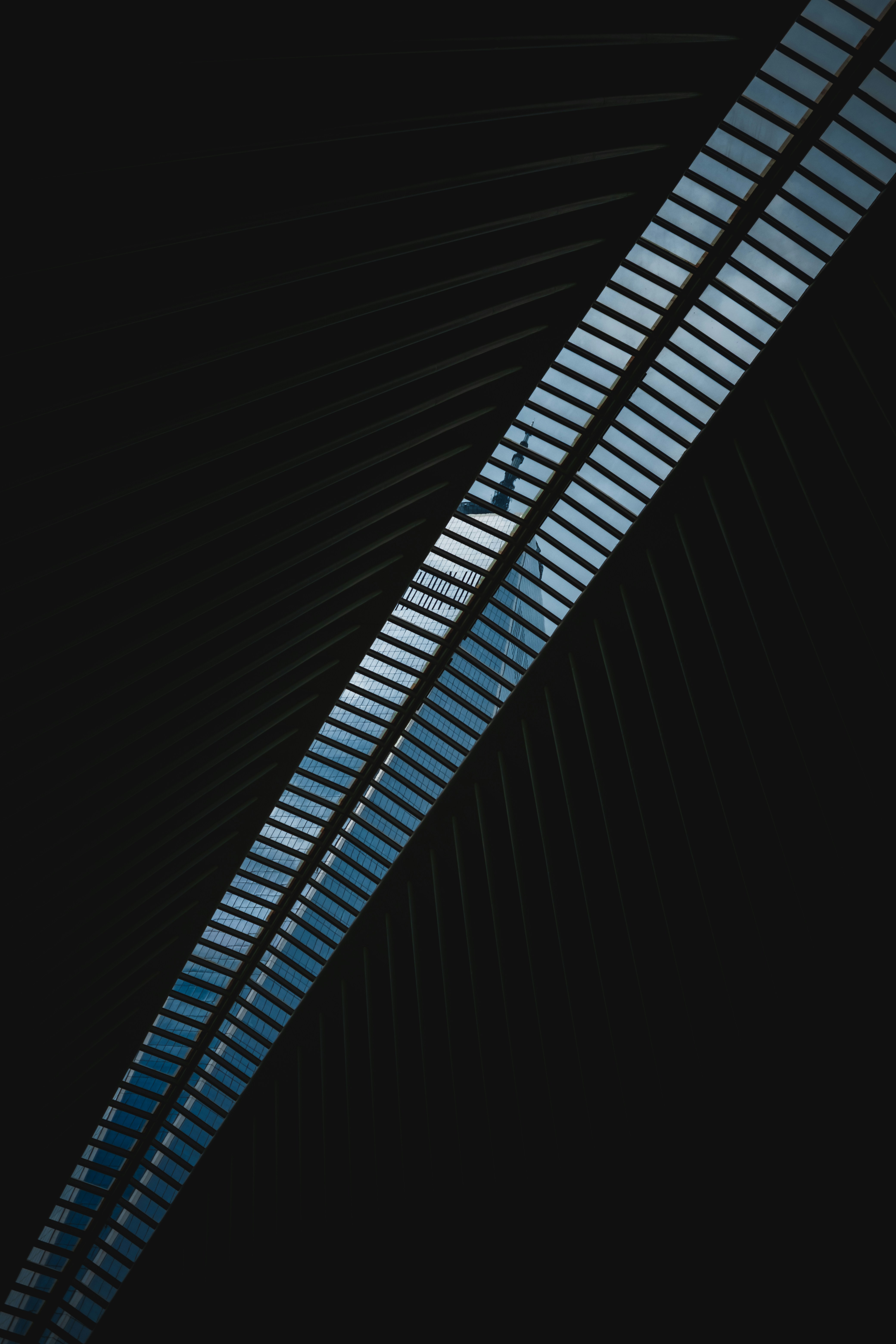 Freedom Tower from inside the Westfield Shopping Center | A dark and angled architectural ceiling with a glimpse of sky.