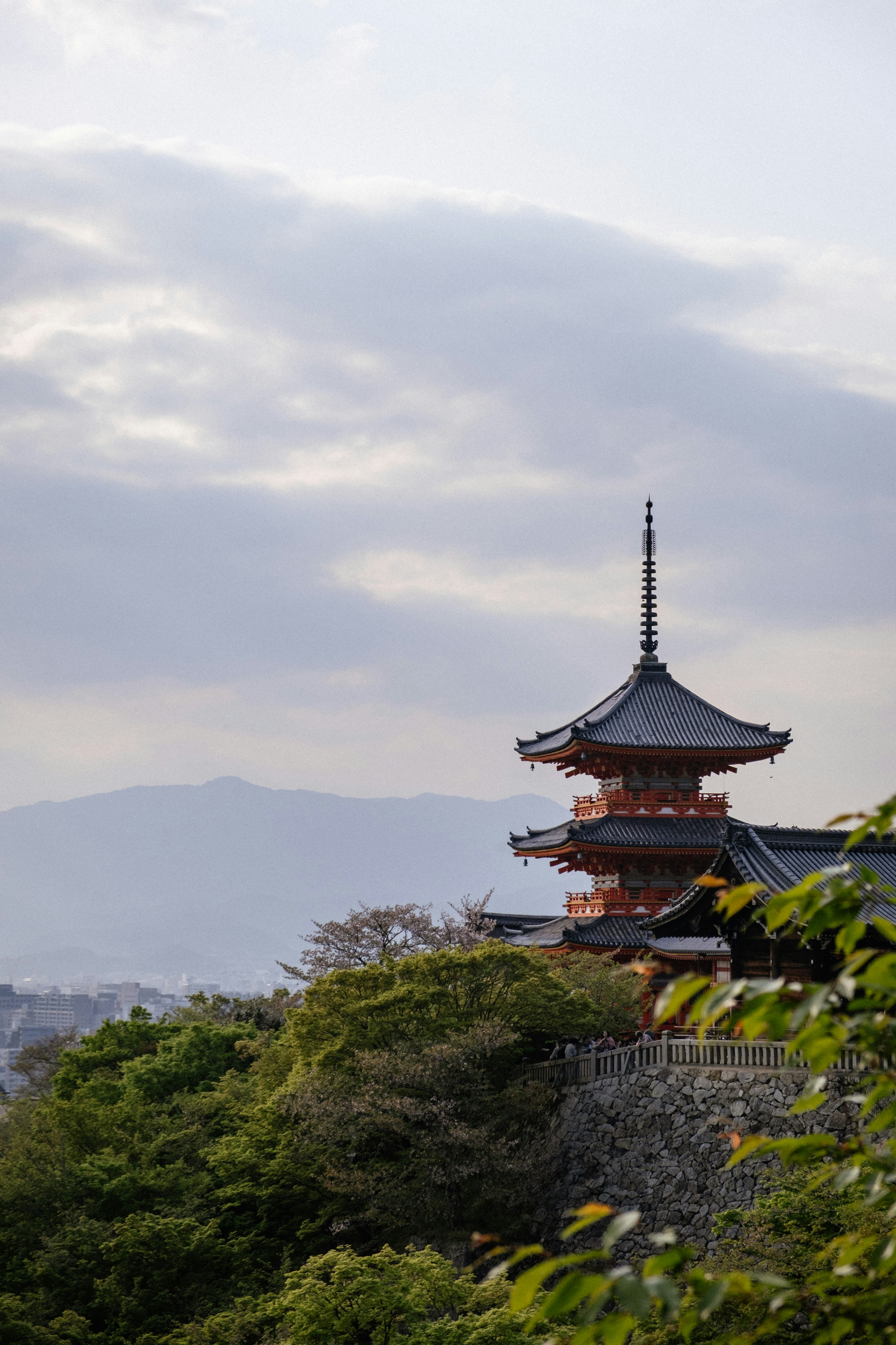 A japanese pagoda rises above green trees.