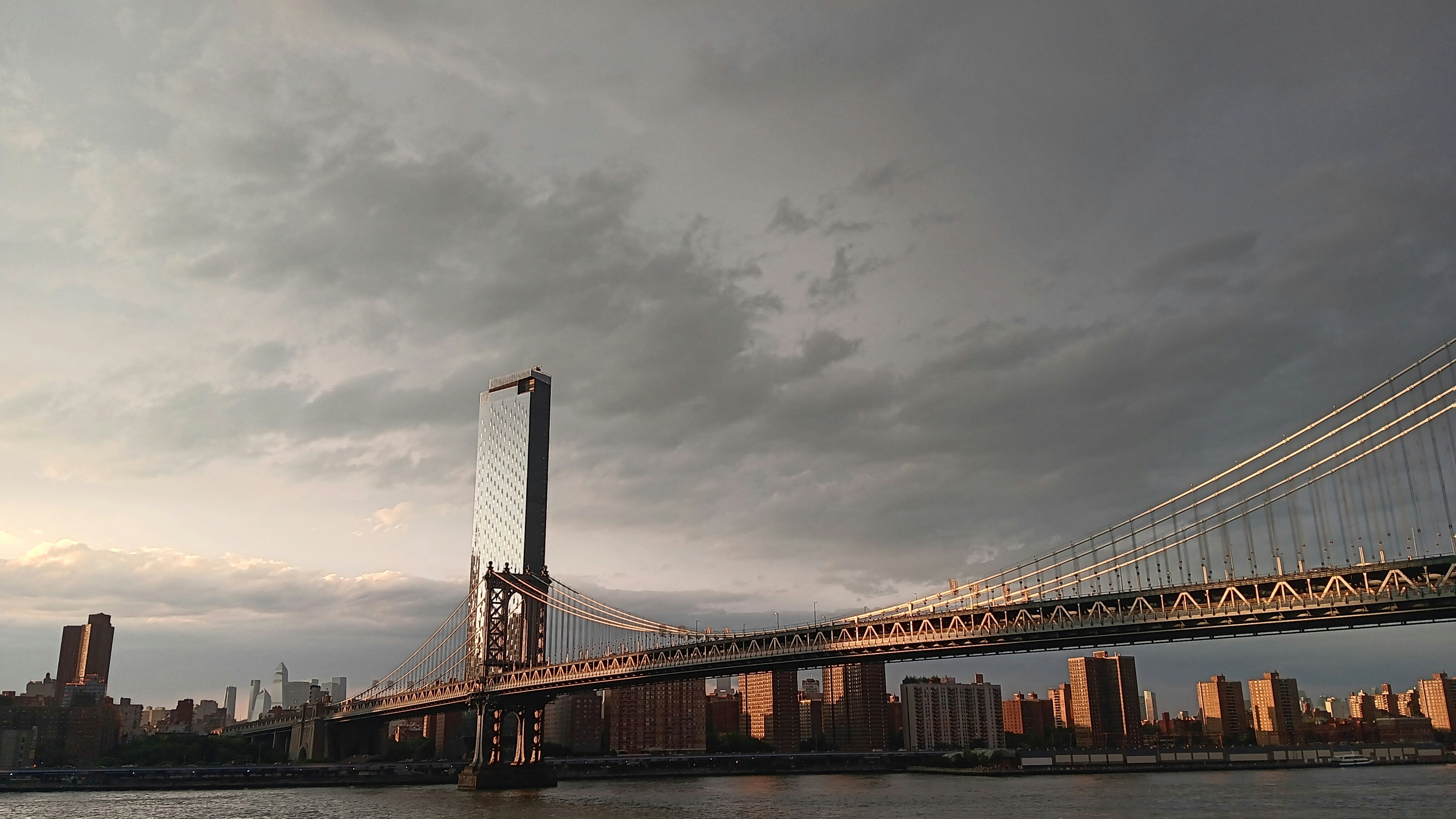 A bridge and skyscraper under a cloudy sky.