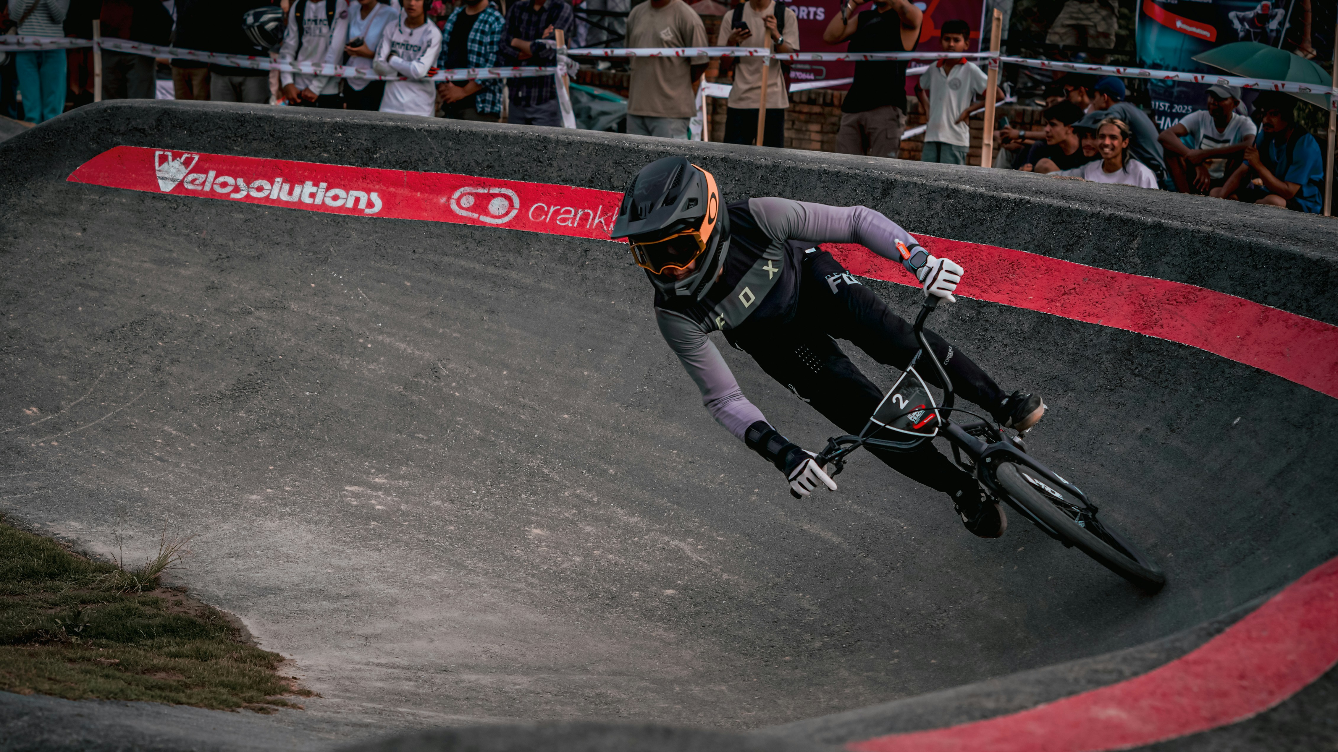 BMX rider expertly navigating a curved track, showcasing skill and speed during a competitive event. The vibrant red branding adds to the dynamic atmosphere.