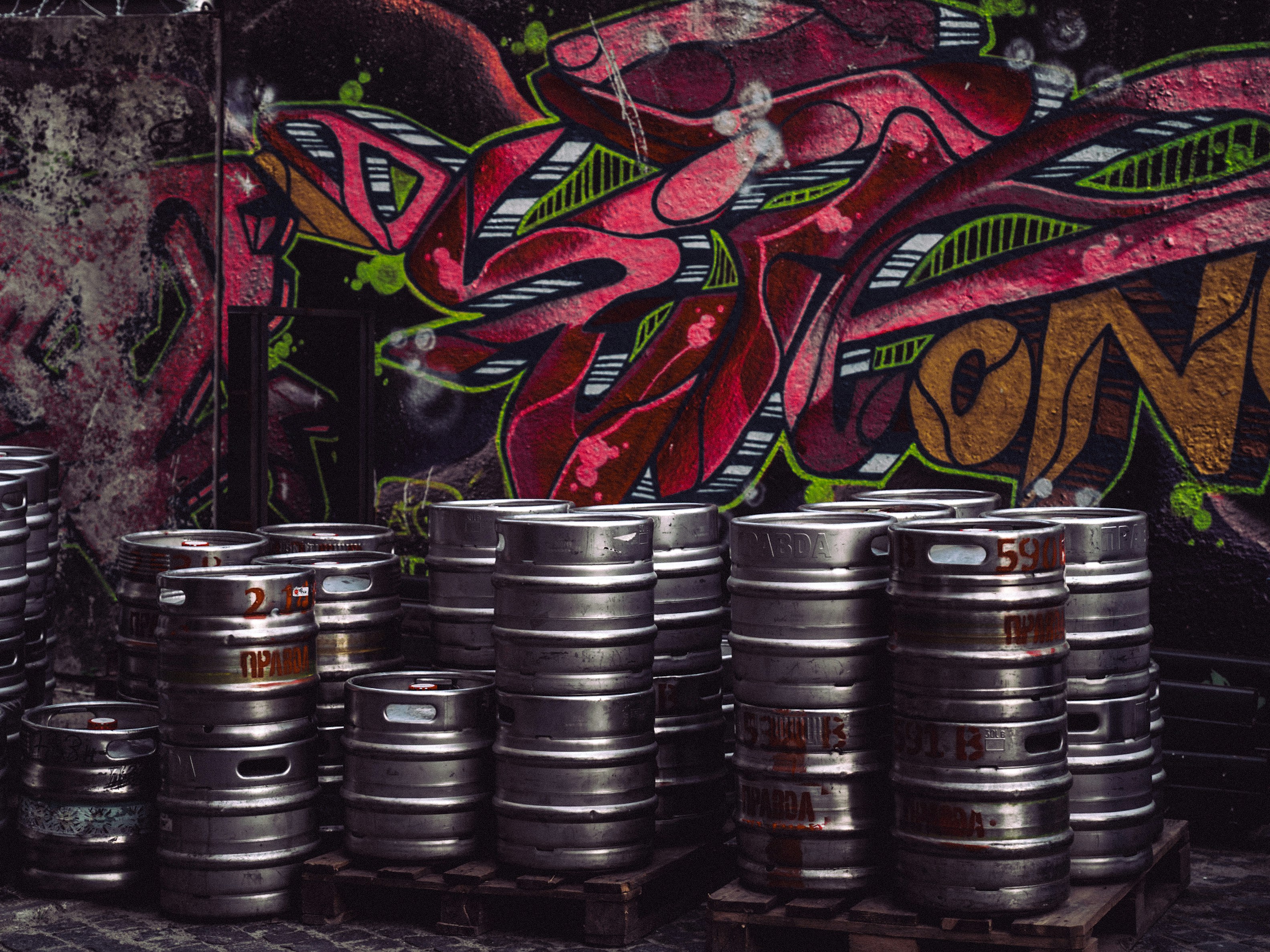 Stacks of Barrels Meet Street Art in a Dim Warehouse