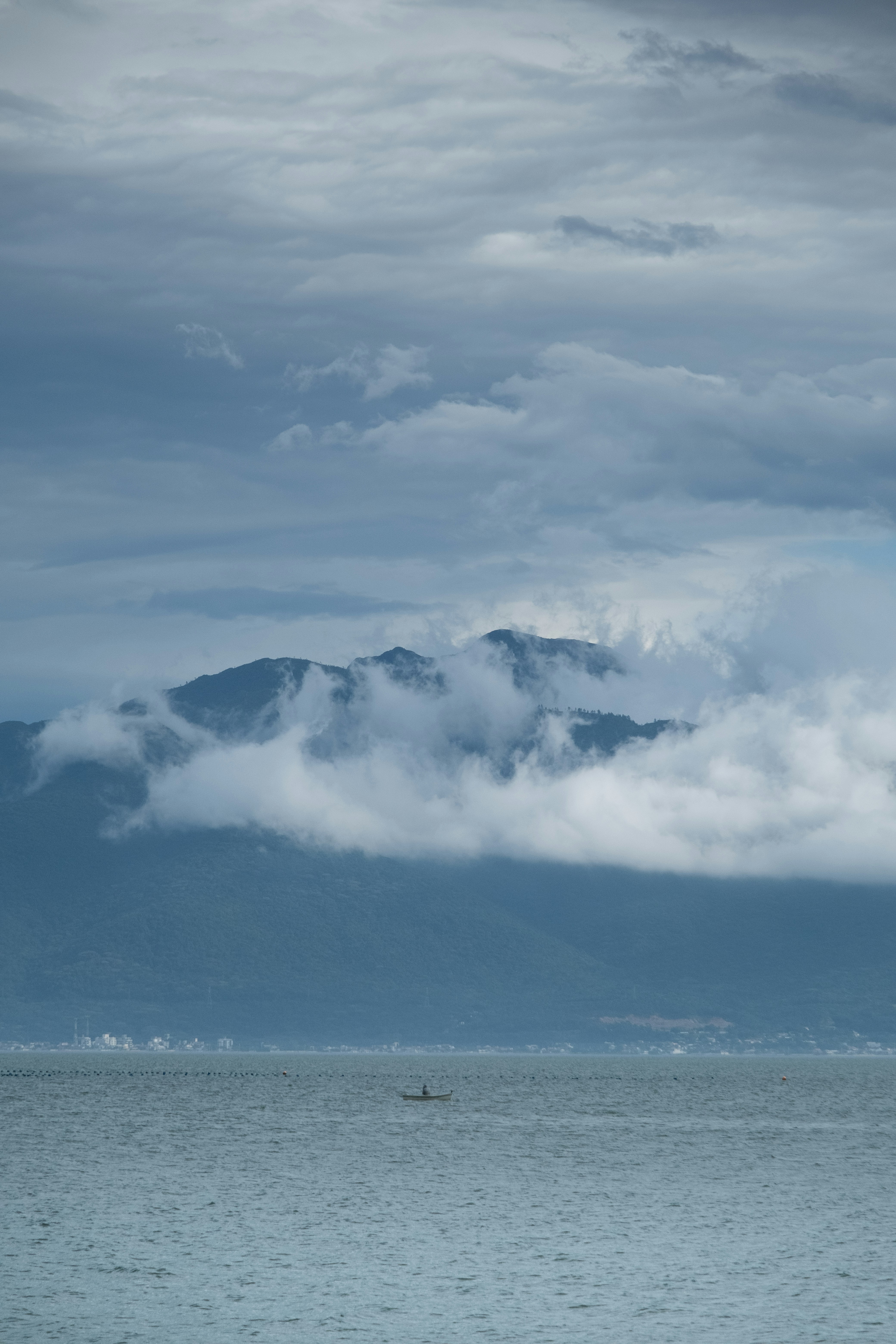 Kayaker navigates calm waters toward mountains.