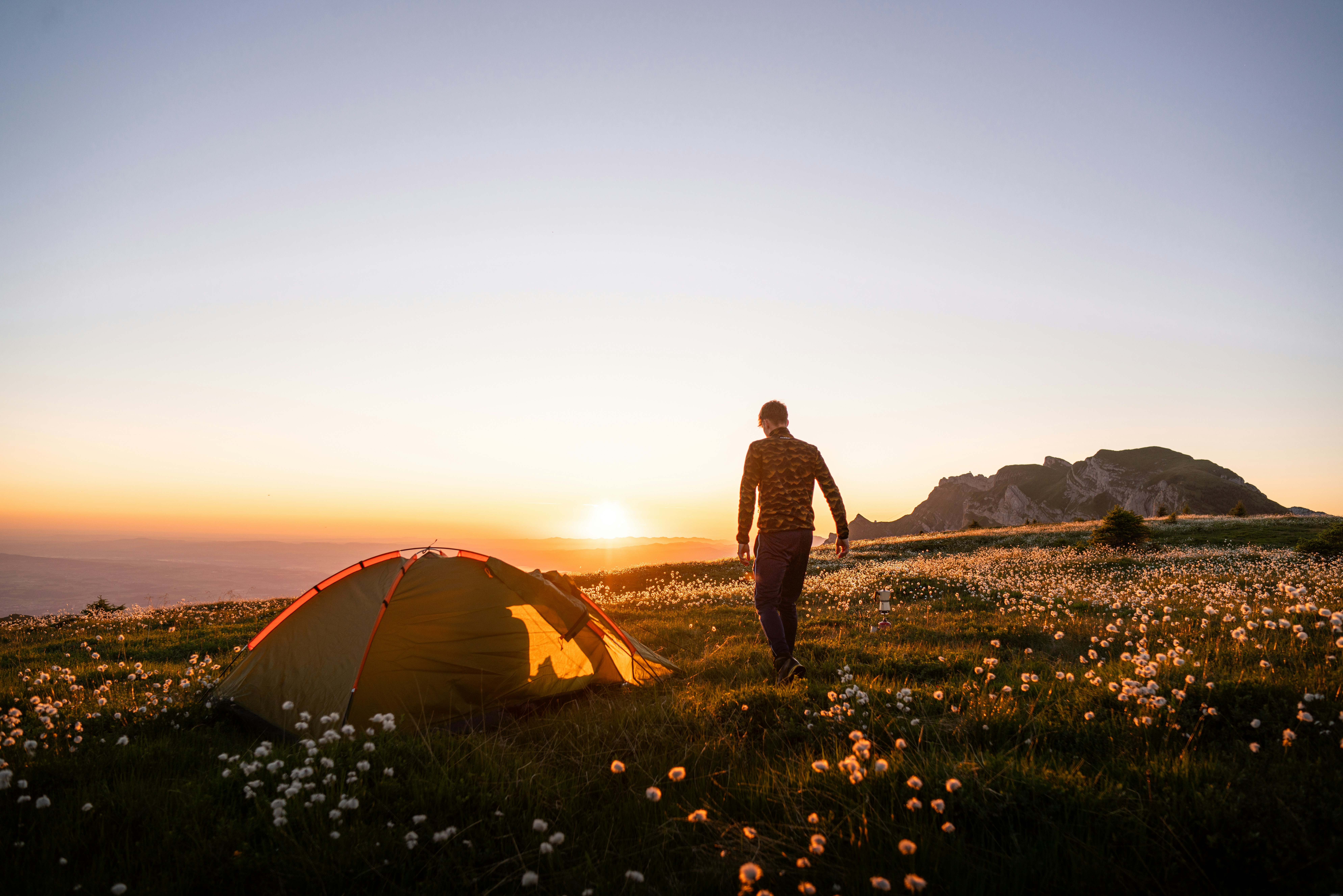 The first sunbeam might be one of the most beautiful sights one can ever see! | Man walks past tent as the sun sets.