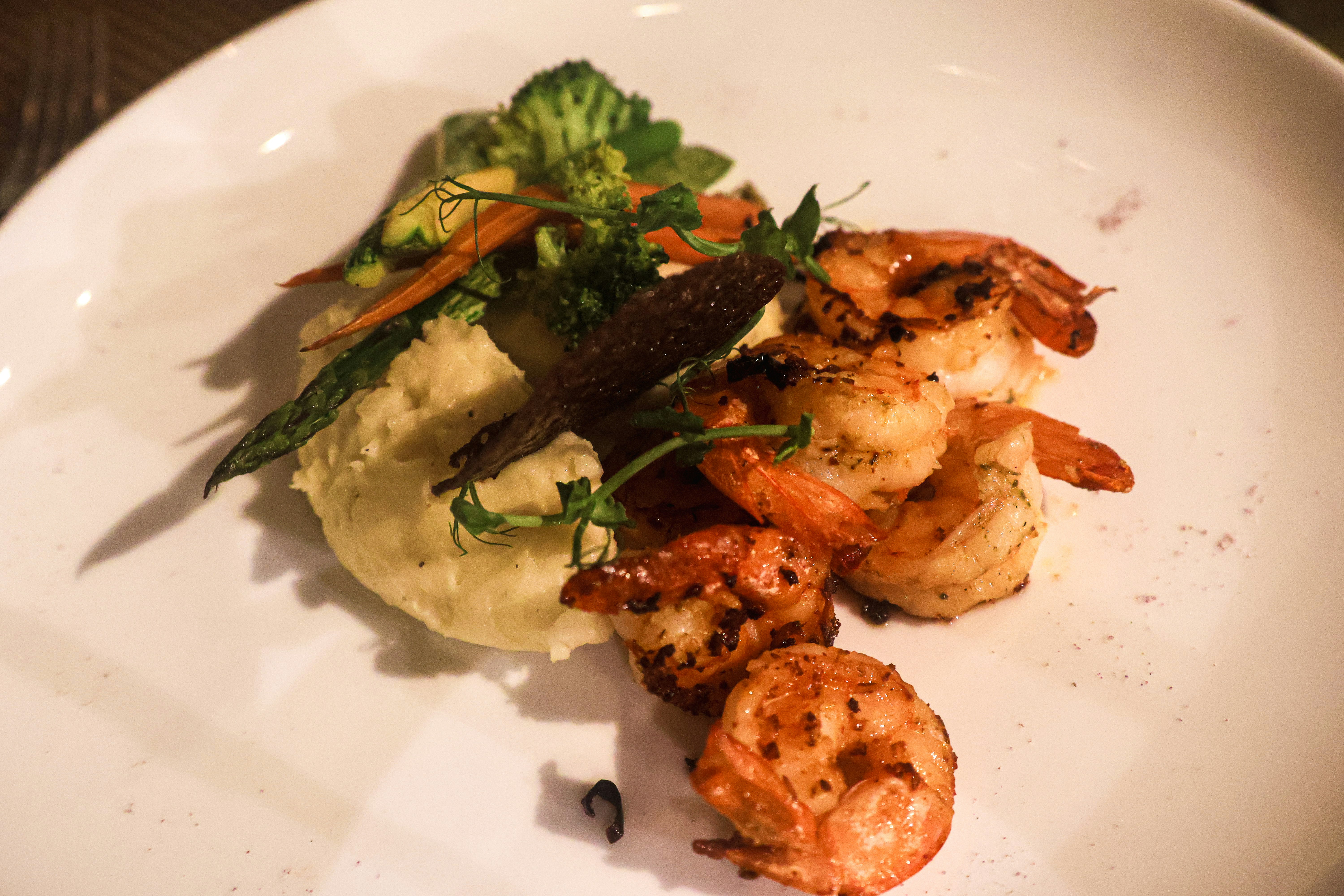 Grilled shrimp elegantly arranged with creamy mashed potatoes and vibrant vegetables, showcasing a delightful culinary presentation.