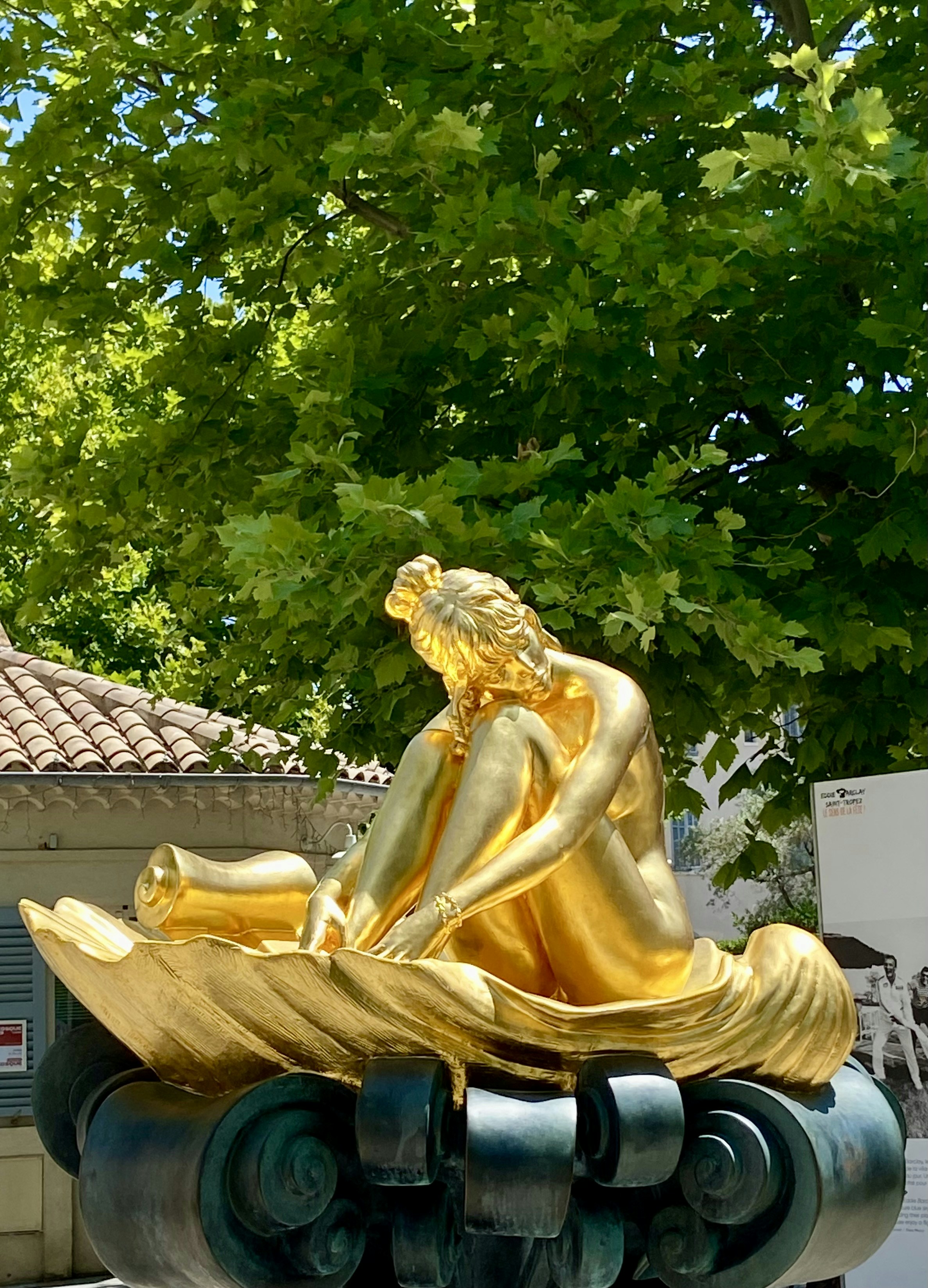 A golden statue sits in a decorative shell.