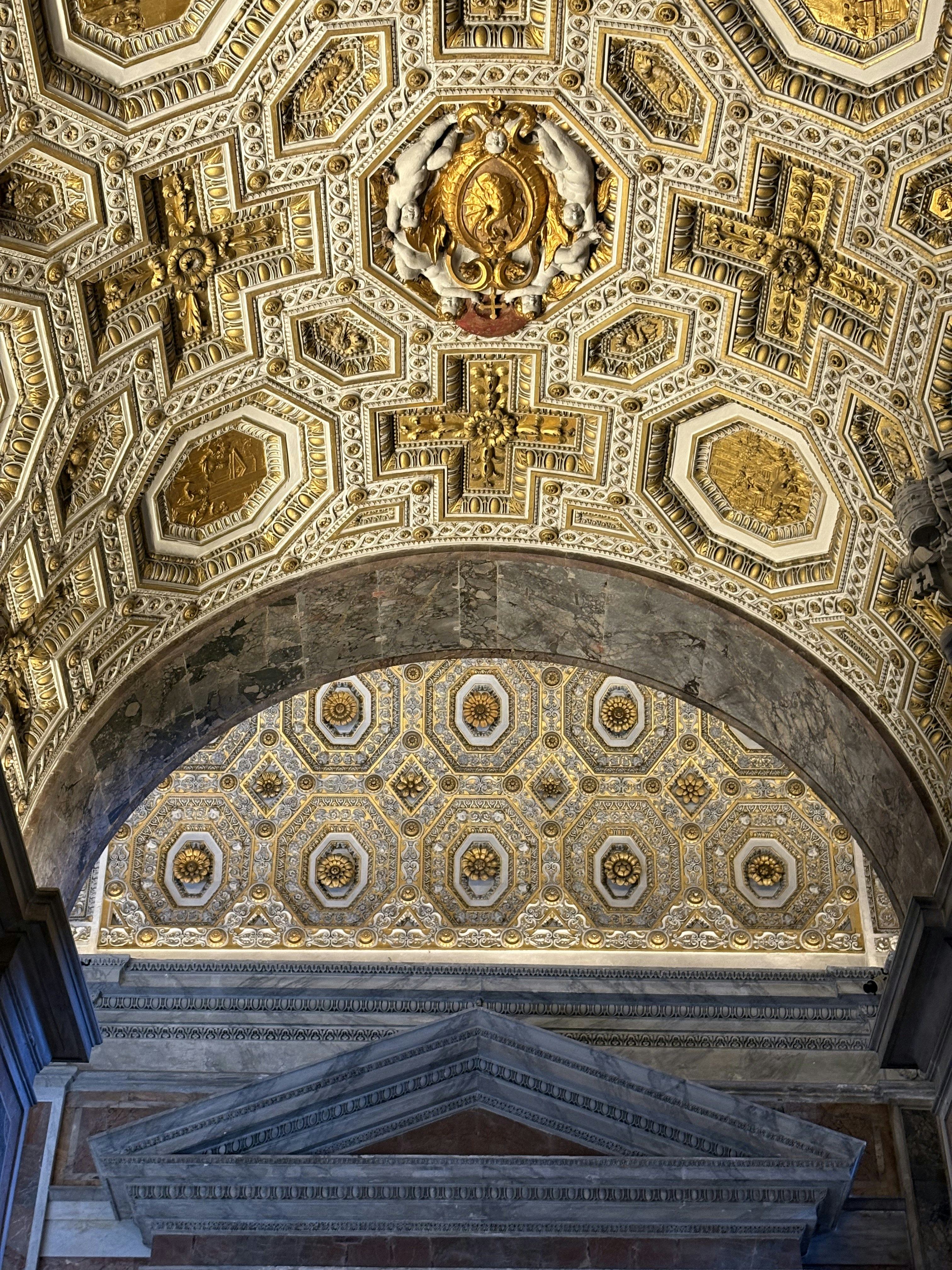 Ornate, gilded ceiling art seen through an arch.