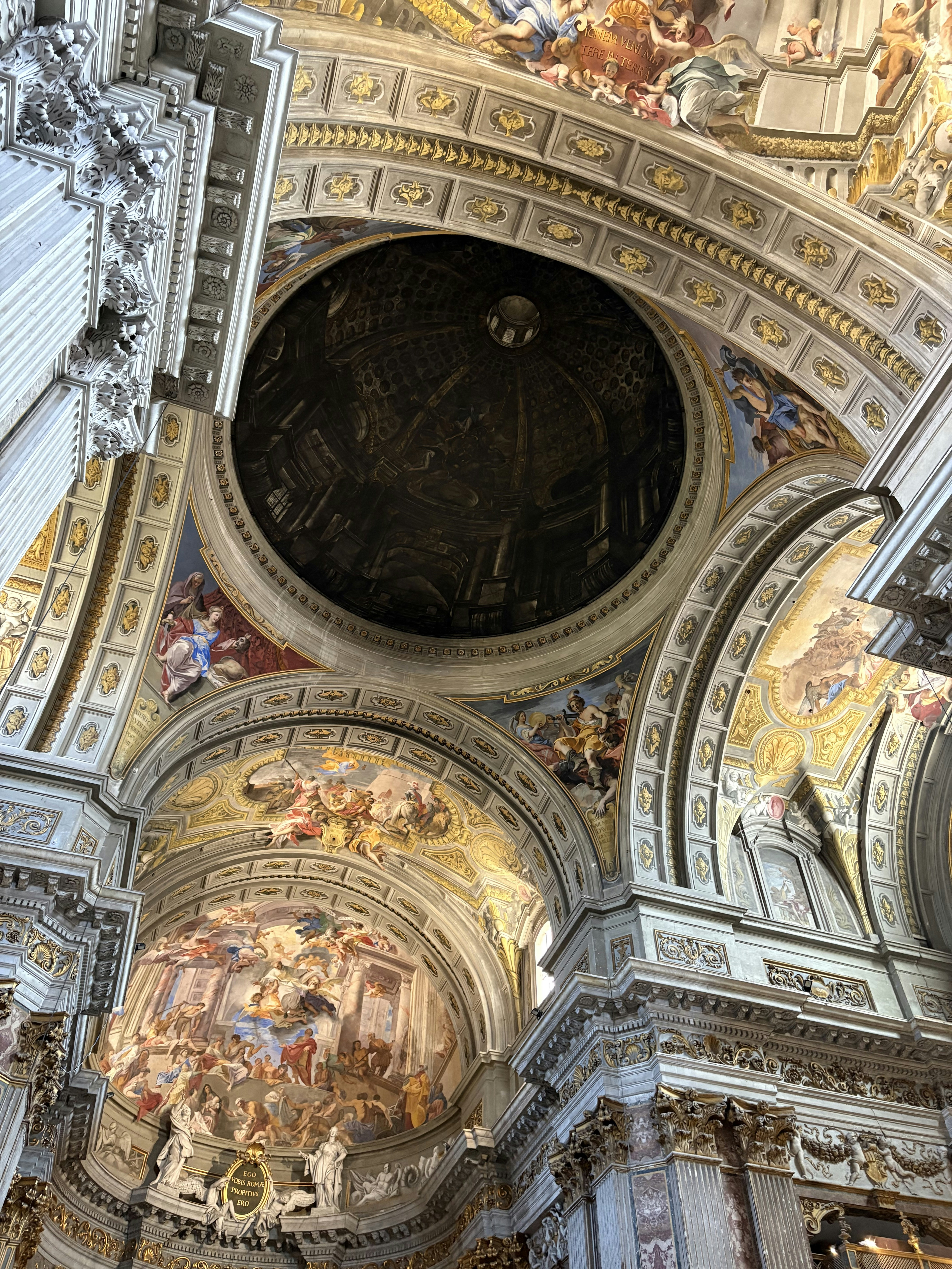 Intricate frescoes and ornate details adorn the grand ceiling of a historic cathedral, showcasing a blend of artistry and architecture.