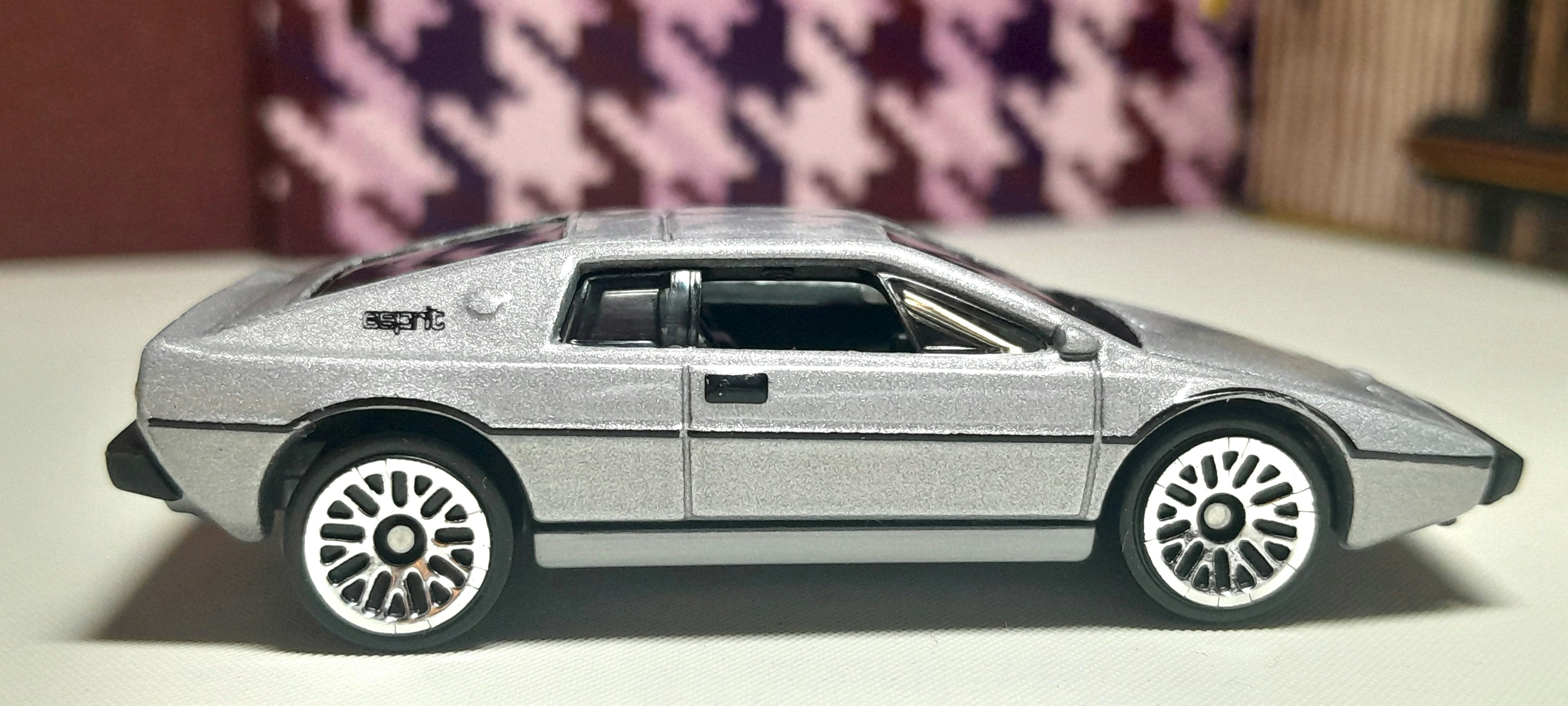 Shiny die-cast toy car photographed from the side on a flat surface, highlighting its metallic body and sculpted wheels.