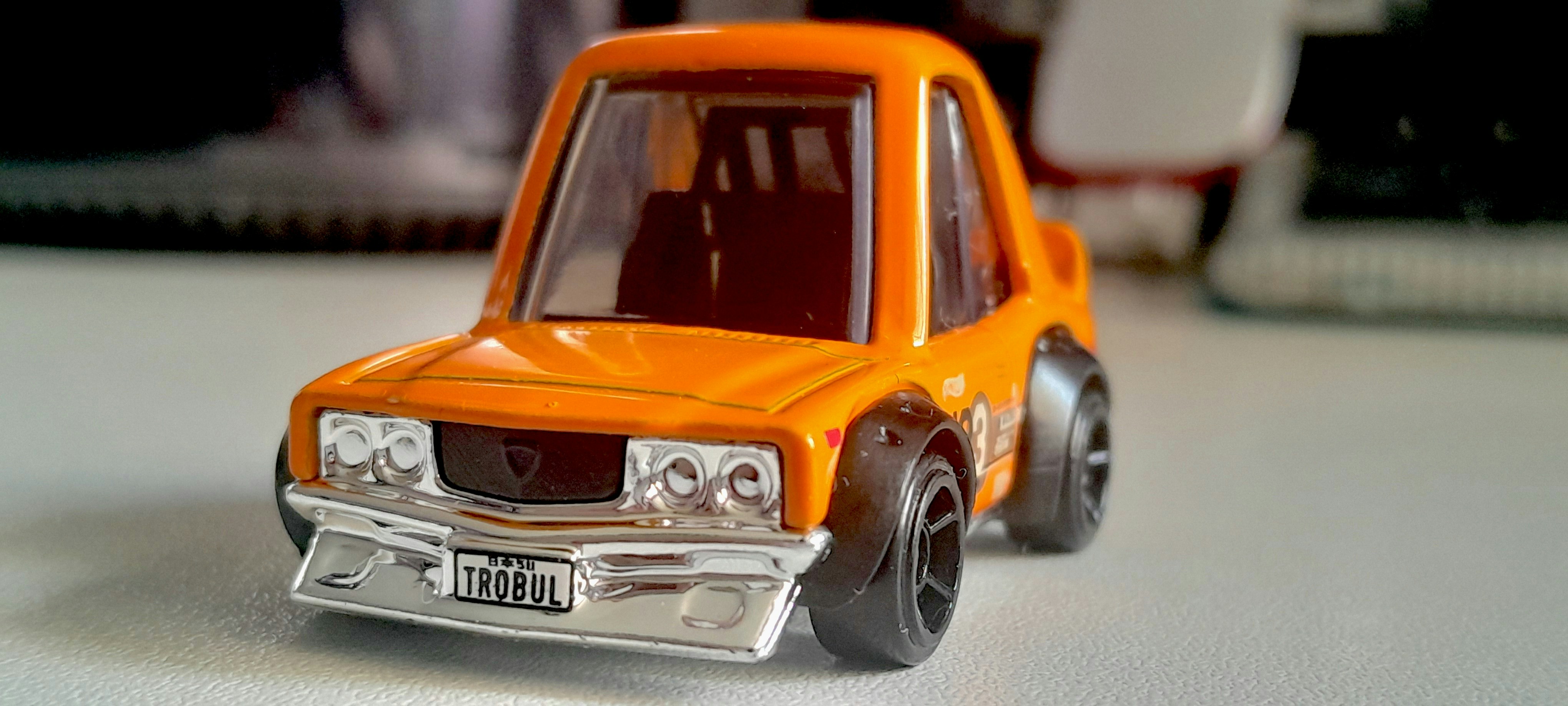 A vibrant orange toy car with a detailed design, showcasing its chrome accents and unique license plate. Perfect for collectors and enthusiasts.