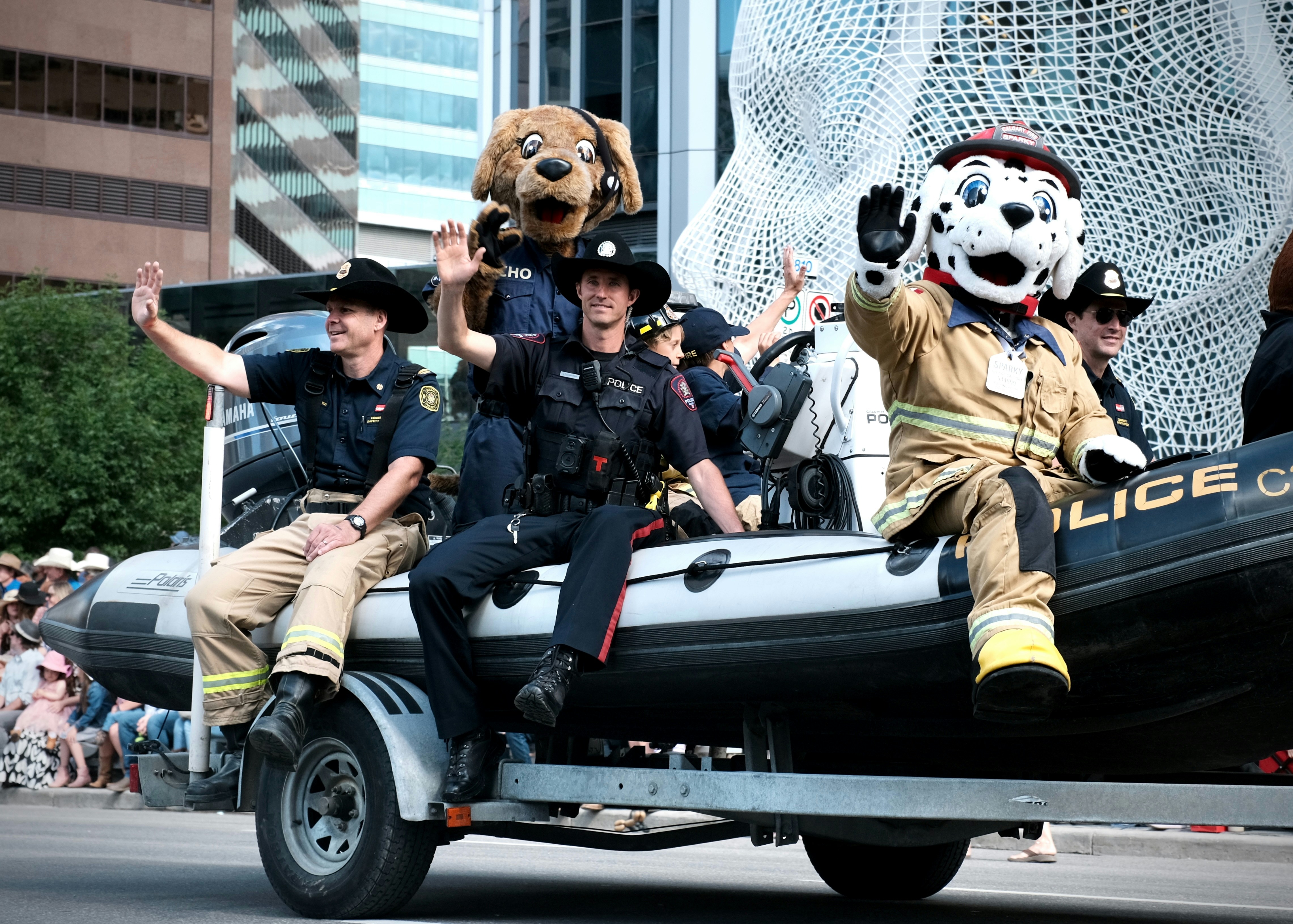 Police and mascots wave during a parade.