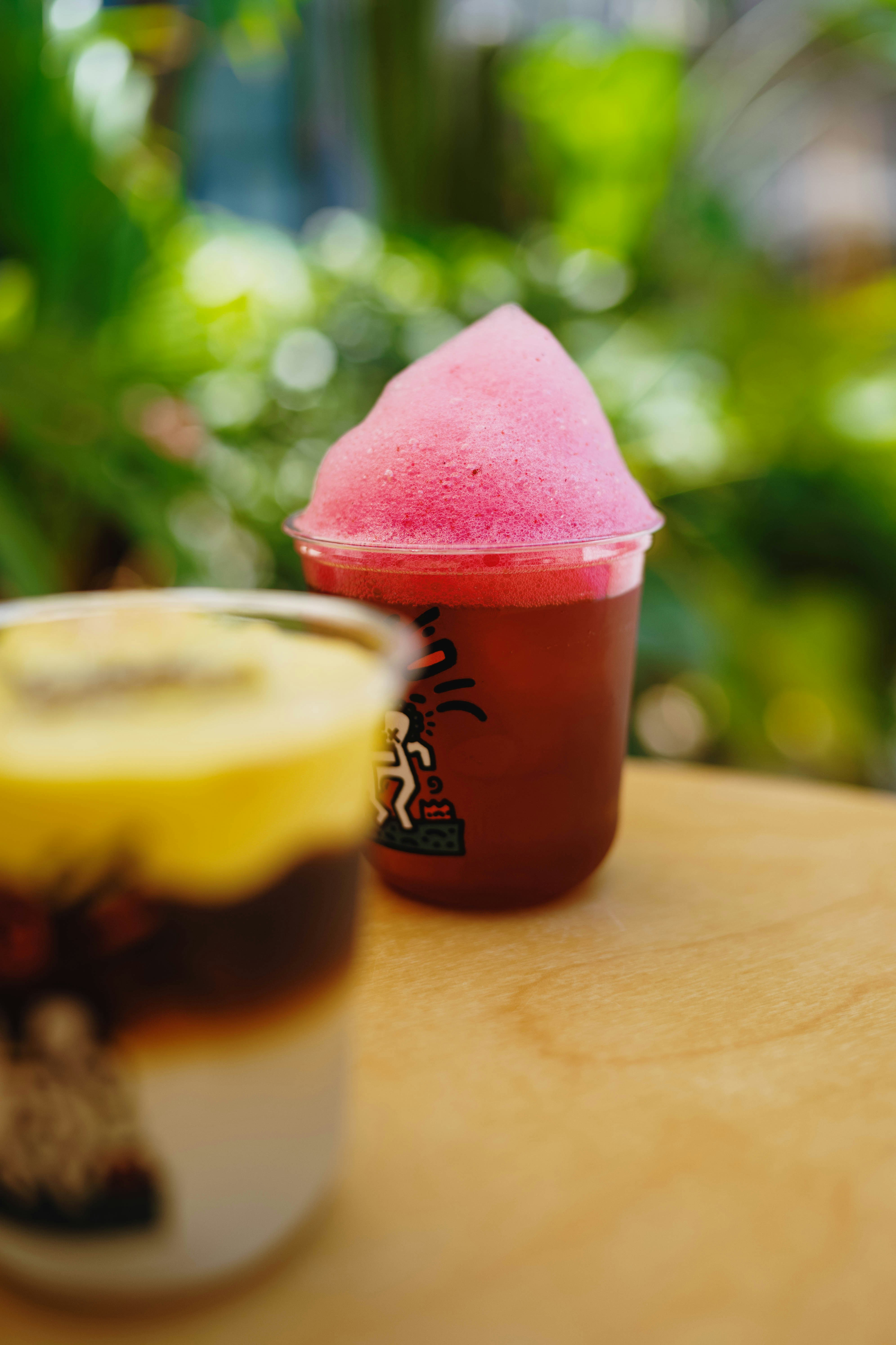 Pink-dome Shaved Foam on a Dark Coffee Cup Crowned by Greenery