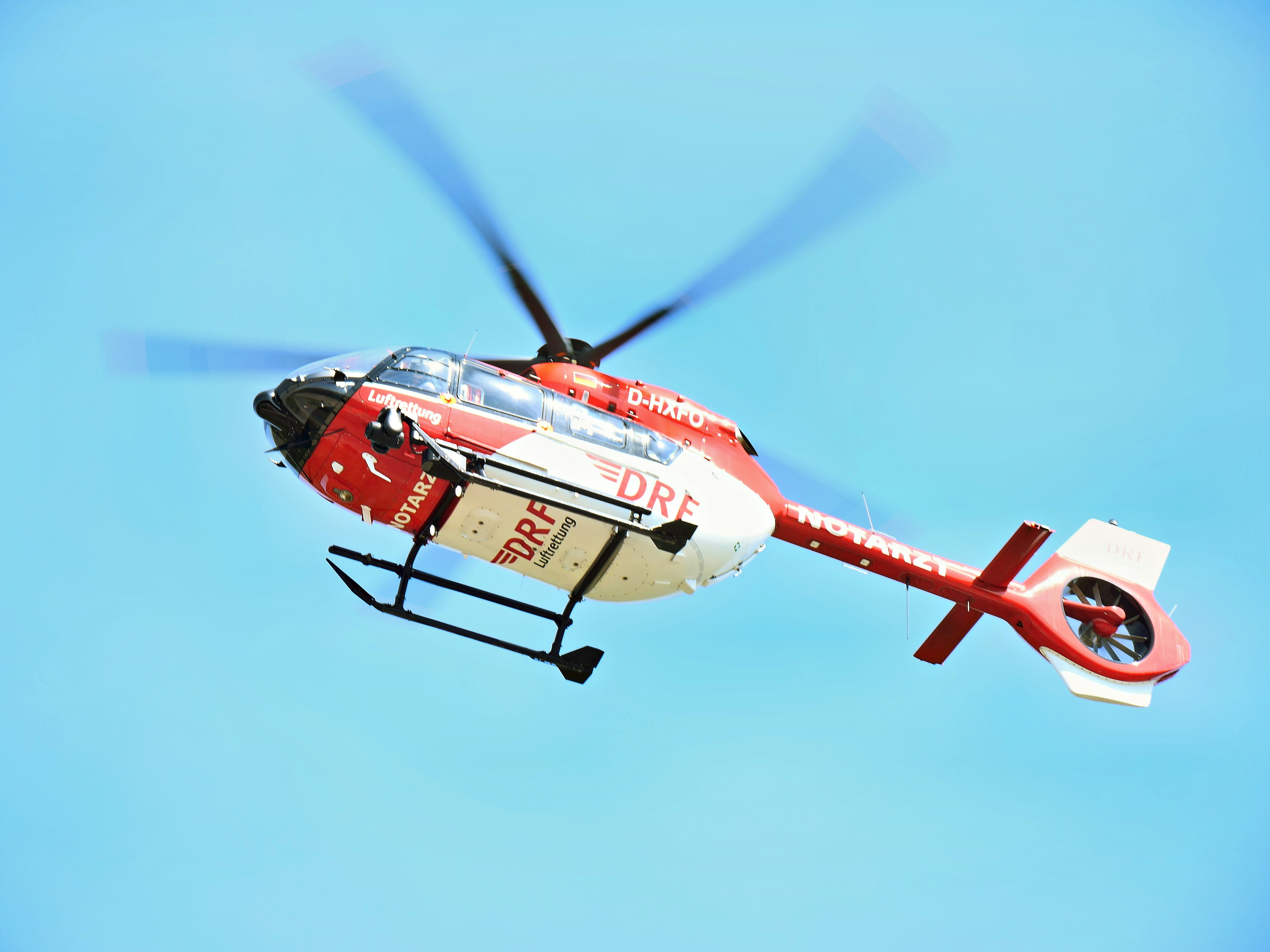A helicopter flies high against a blue sky.