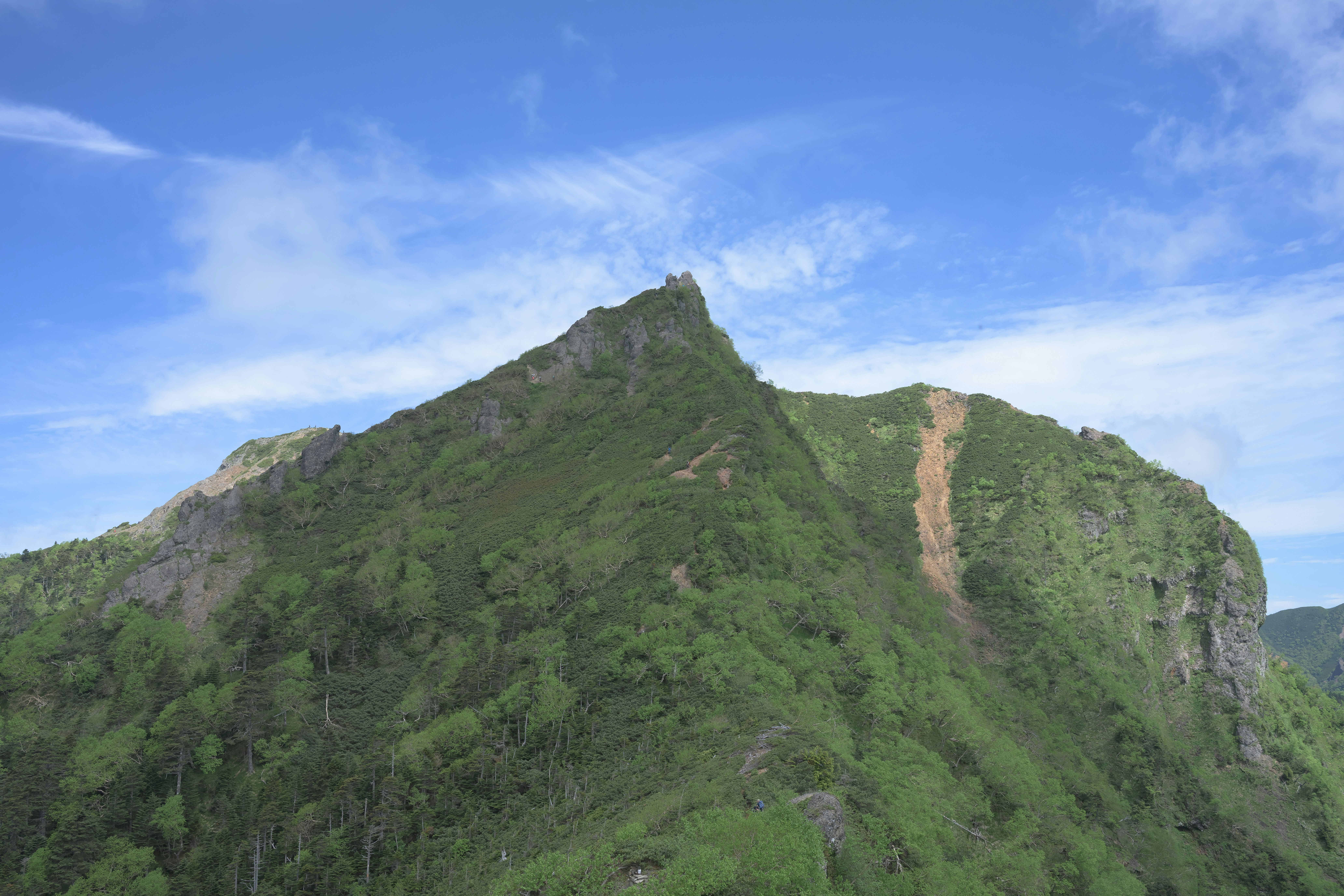 A green mountain against a blue sky.