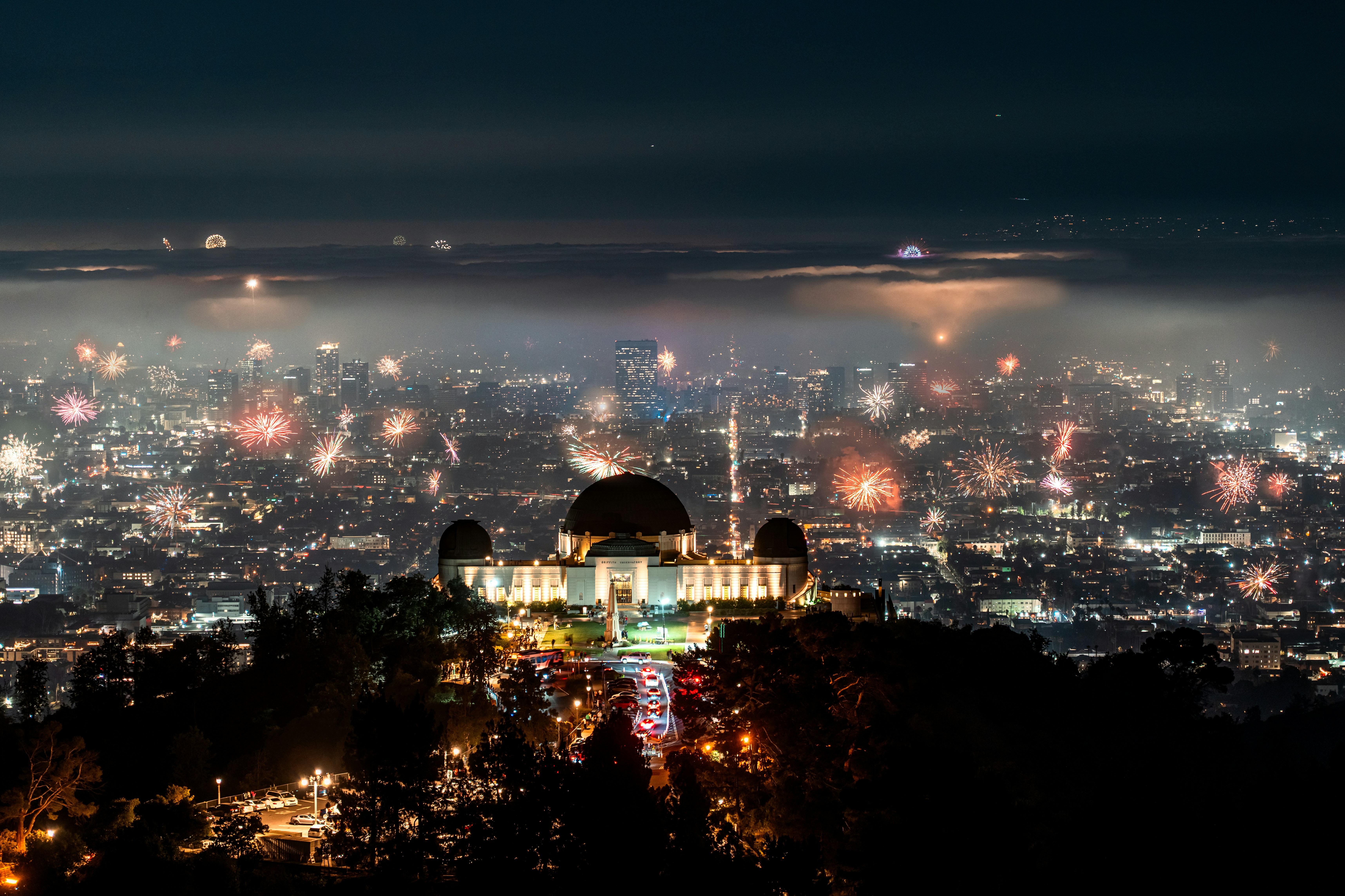 Fireworks illuminate the night sky over a city.