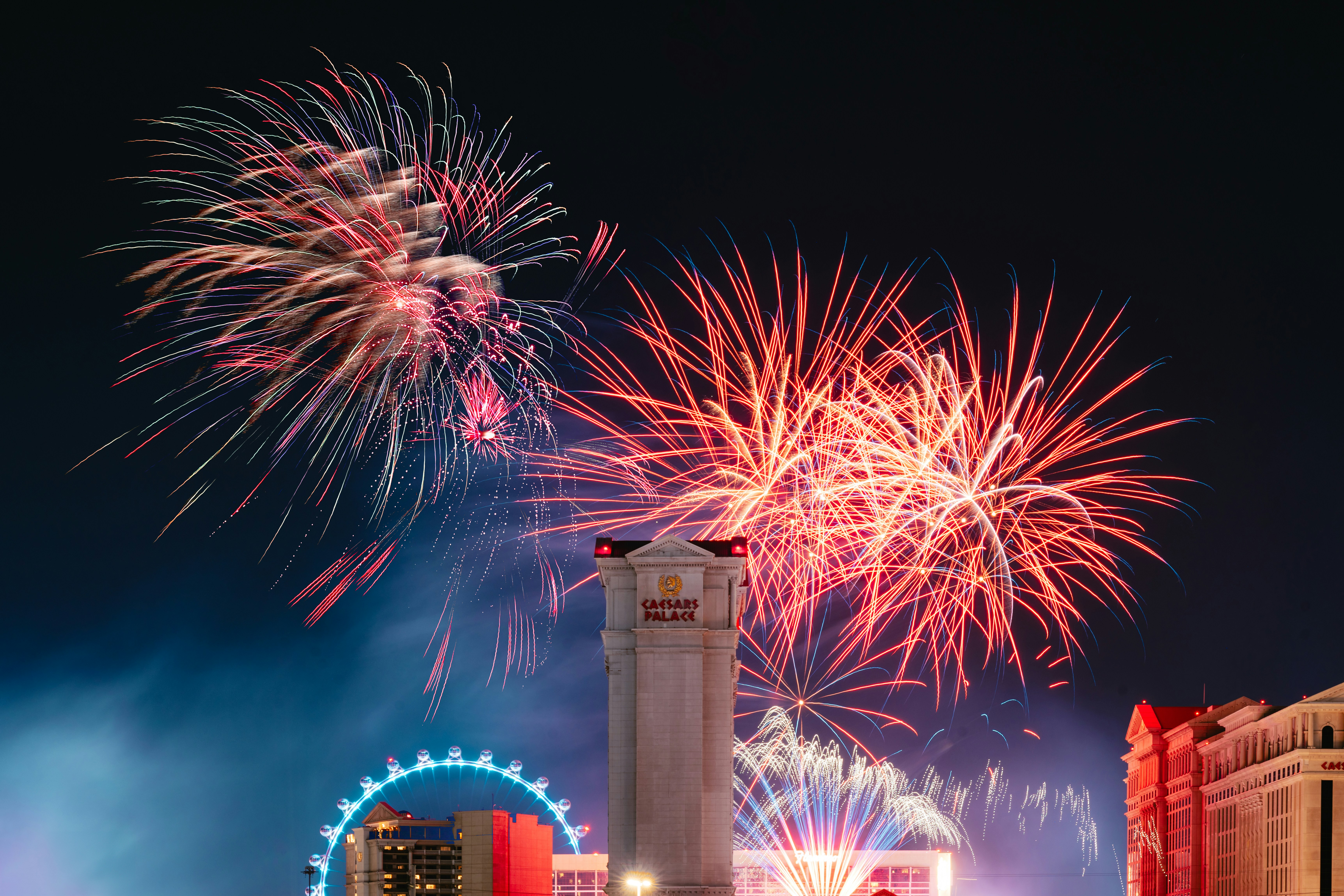 Colorful fireworks illuminate the night sky above a vibrant city skyline, showcasing a blend of excitement and celebration.