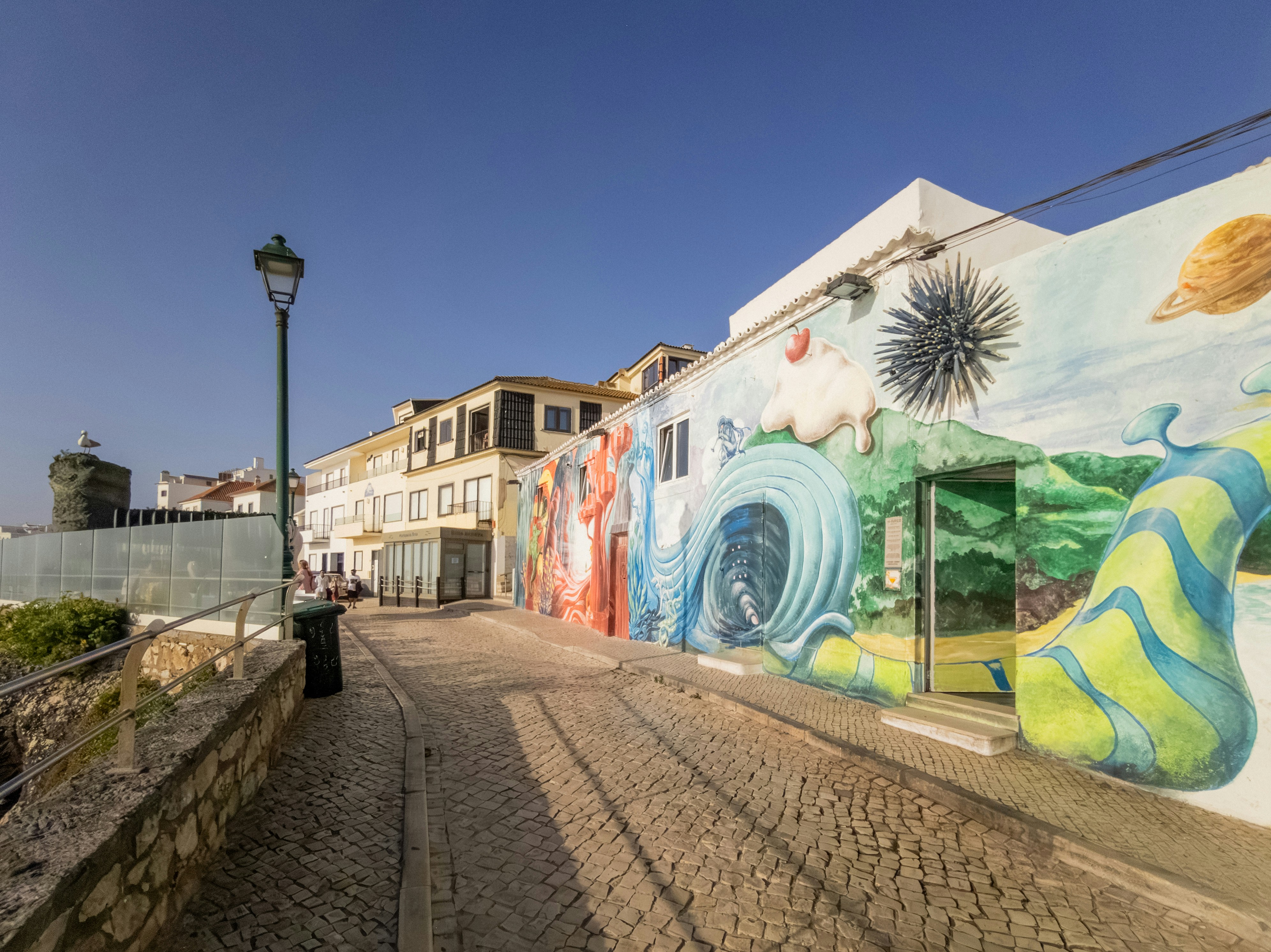 Ouriço Night Club | A street with vibrant murals adorns the wall.