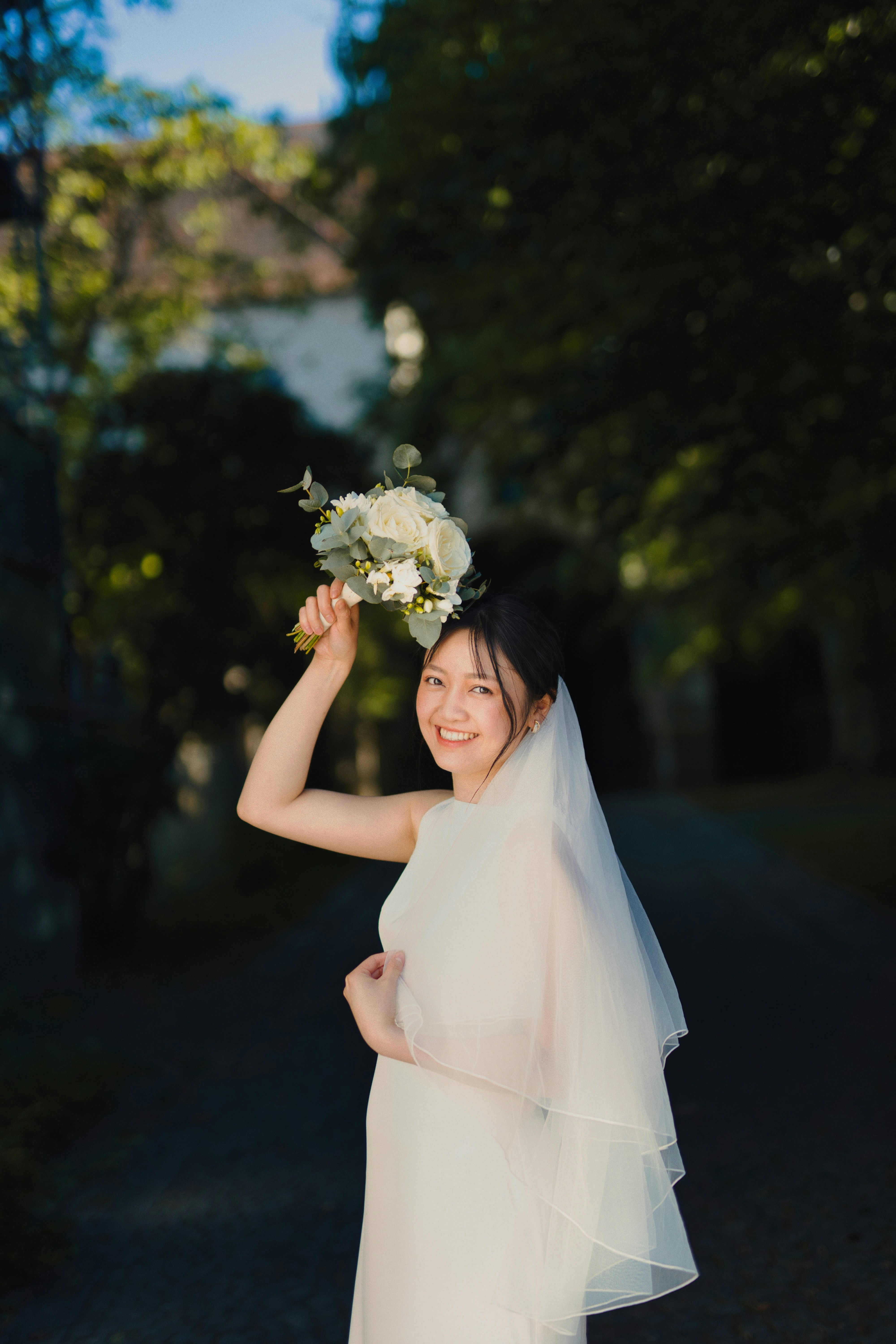 Wedding dress | Bride happily poses with her bouquet and veil.