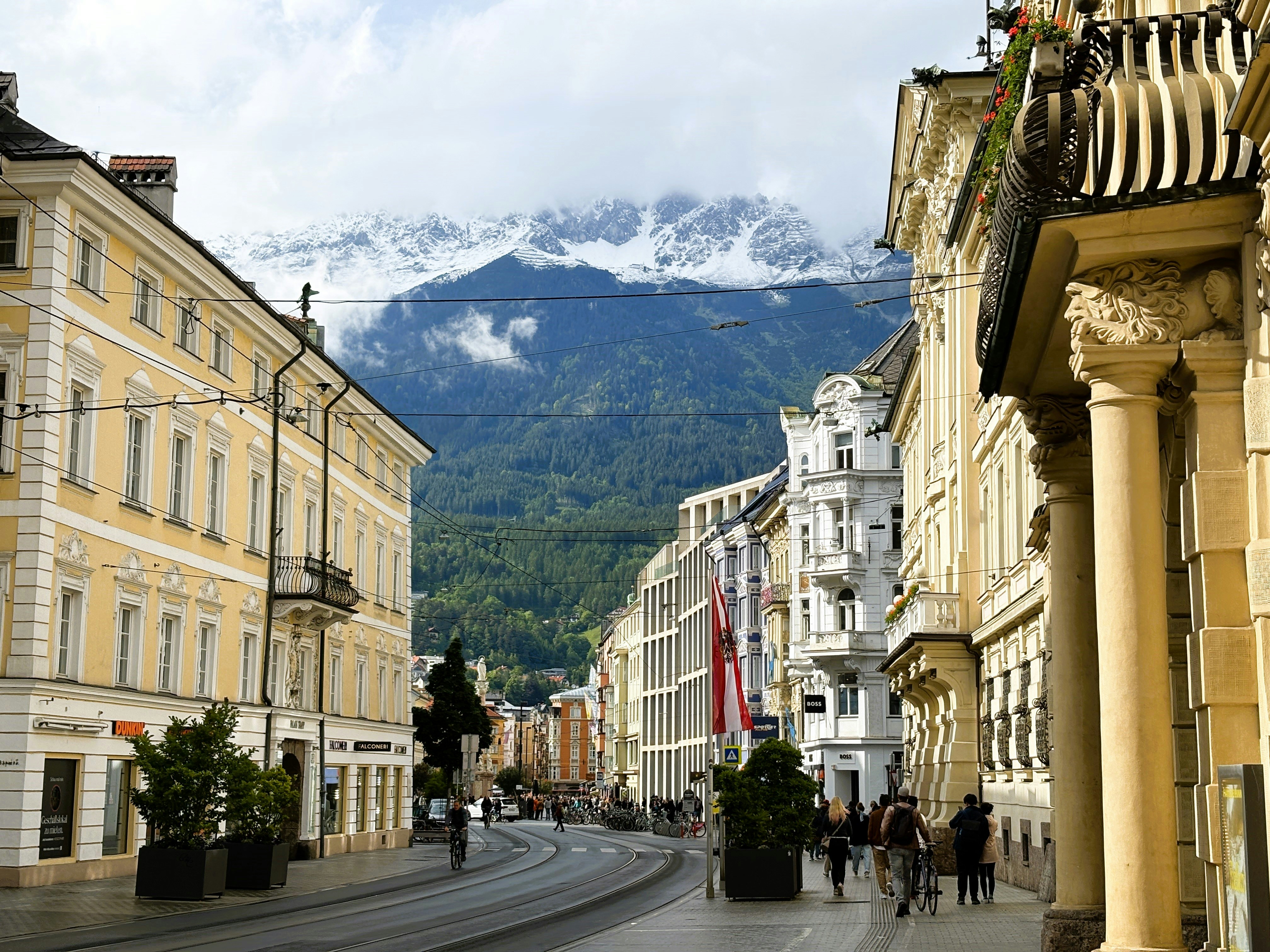 Charming street scene in Innsbruck showcasing elegant architecture with snow-capped mountains in the background. The vibrant atmosphere invites exploration.