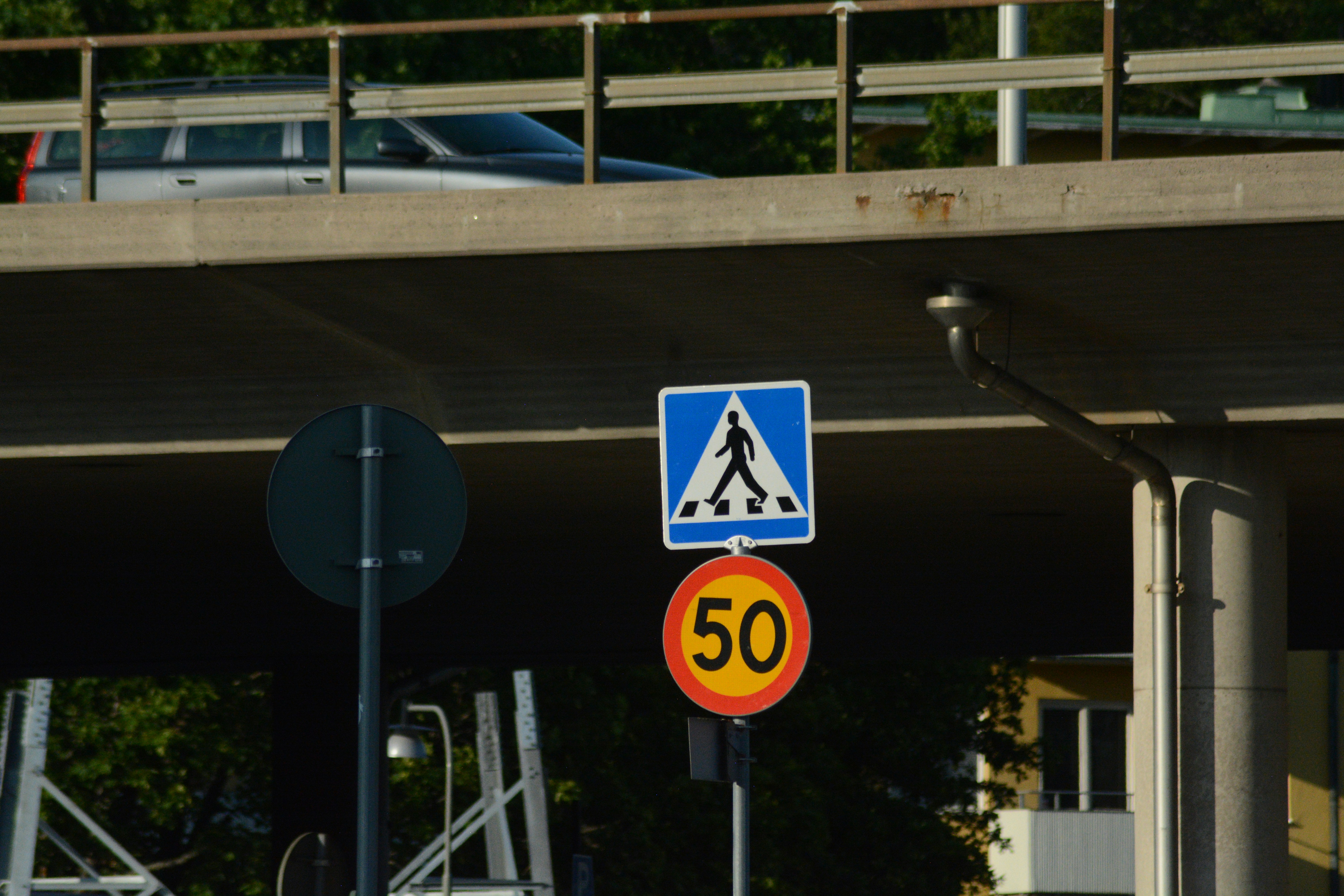 Traffic signs indicate a pedestrian crossing and speed limit.