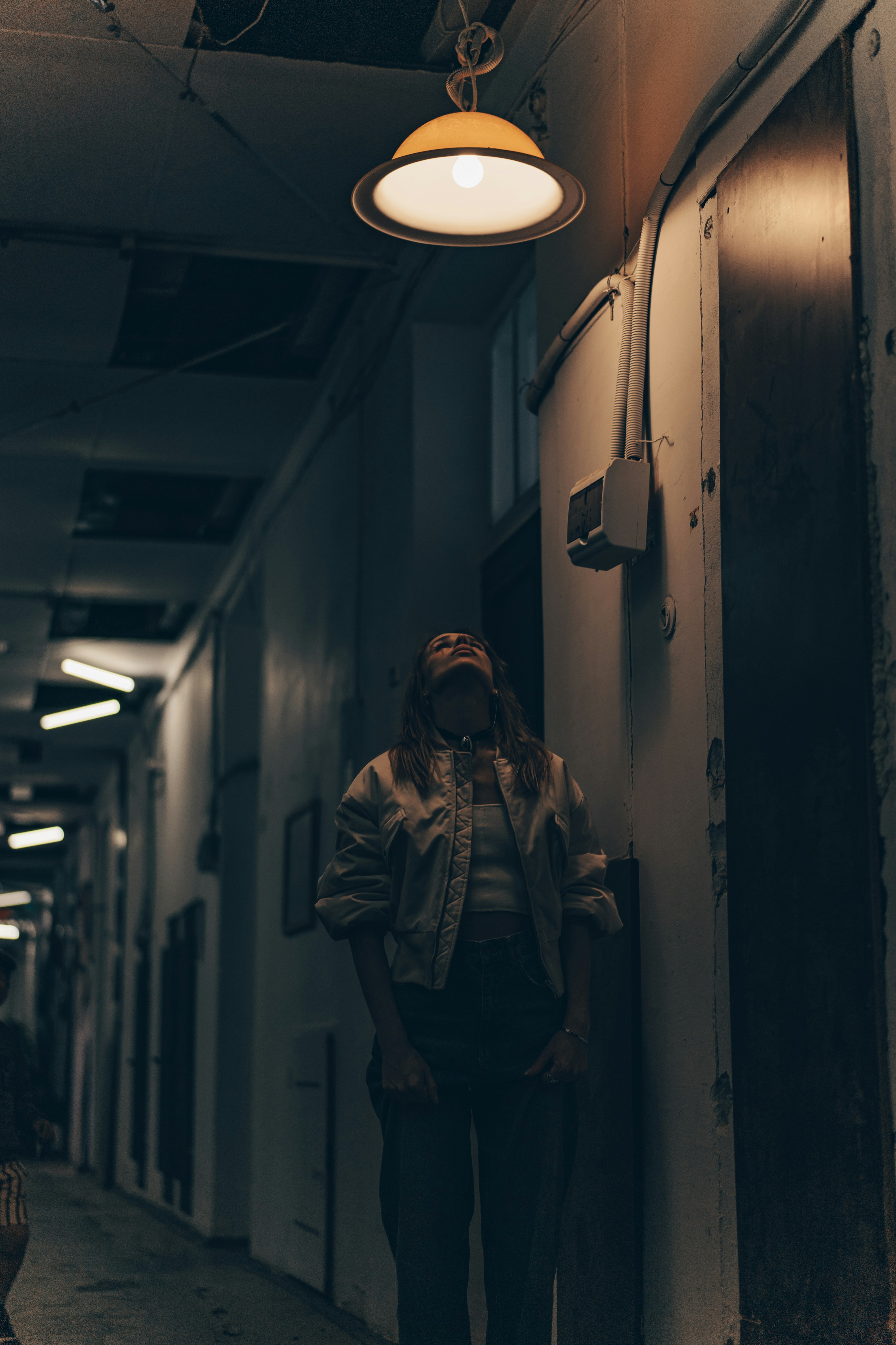 Вавилов Лофт, Saint Petersburg, Russia | Woman looks up at a bright light in a hallway.