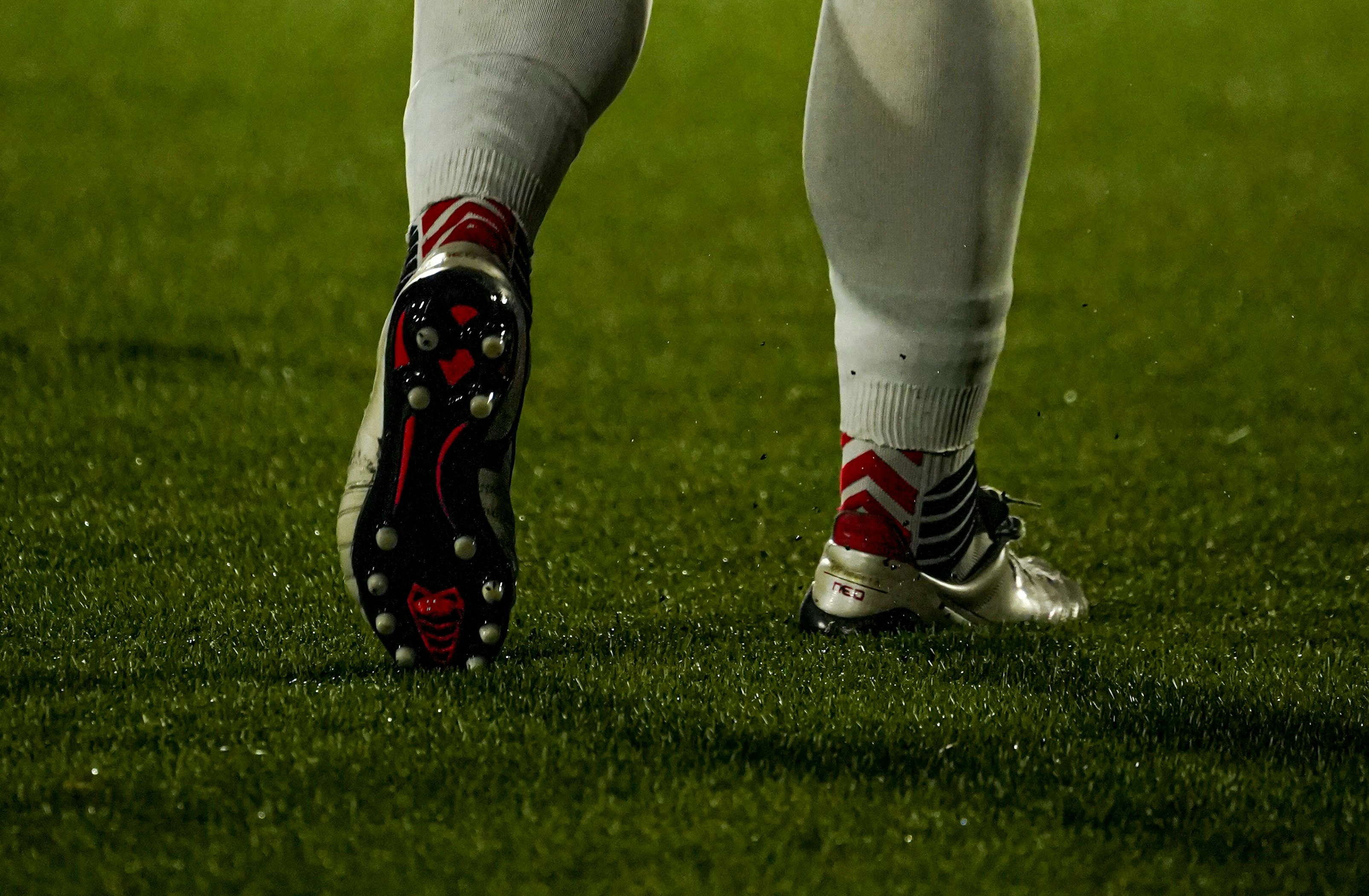 Football player's legs and cleats on the grass.