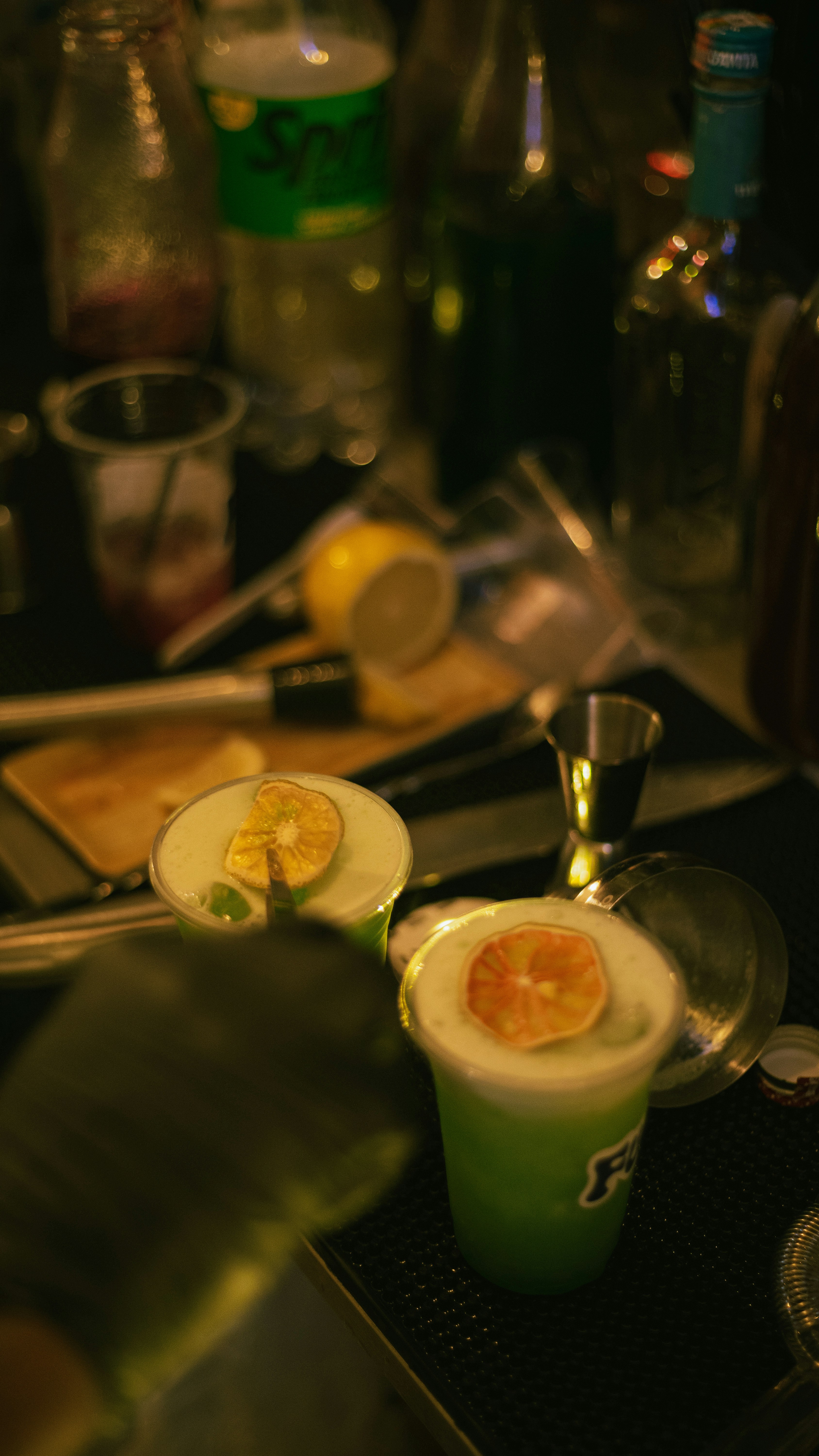 Two green cocktails with orange slices.