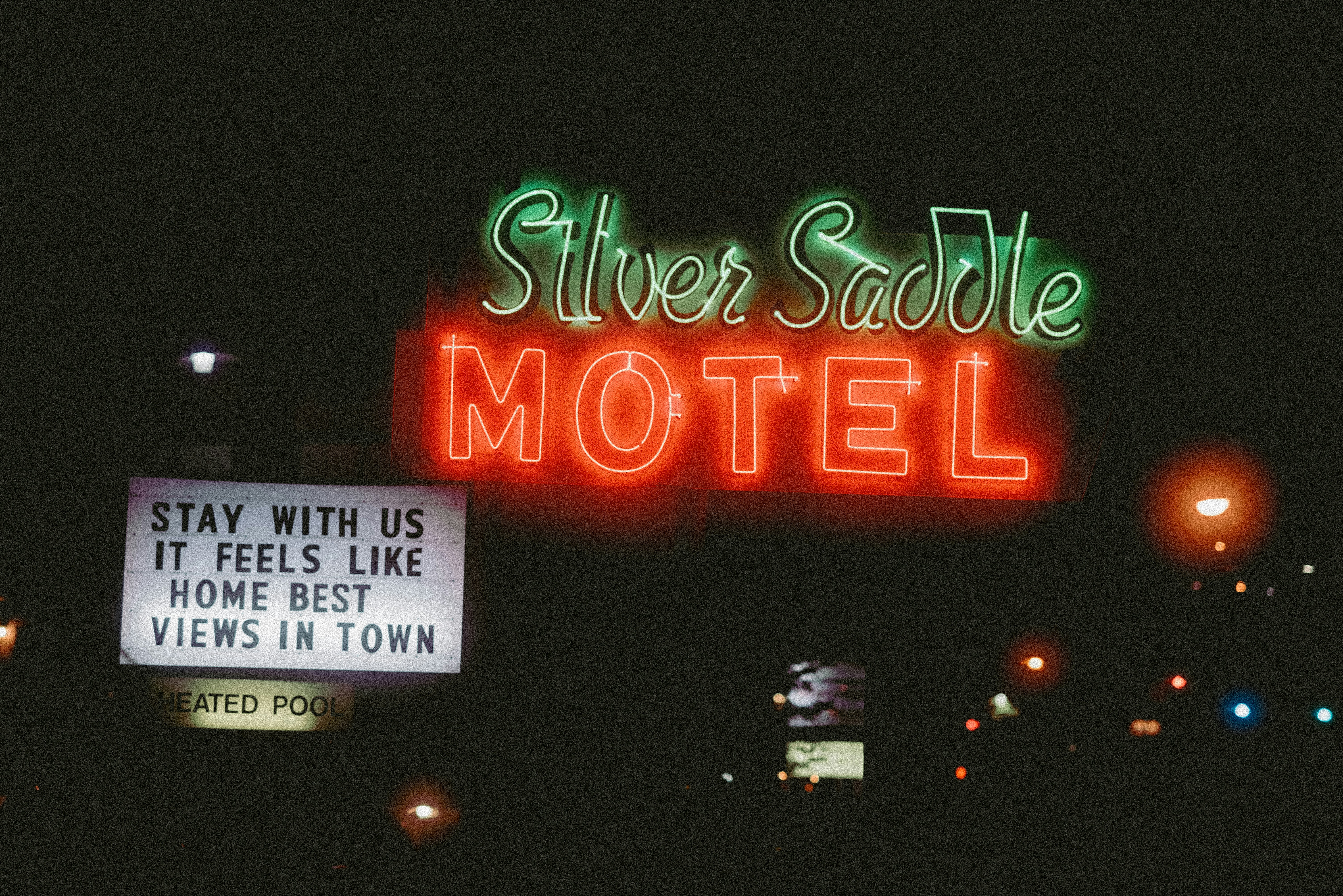 A neon sign for silver saddle motel at night.