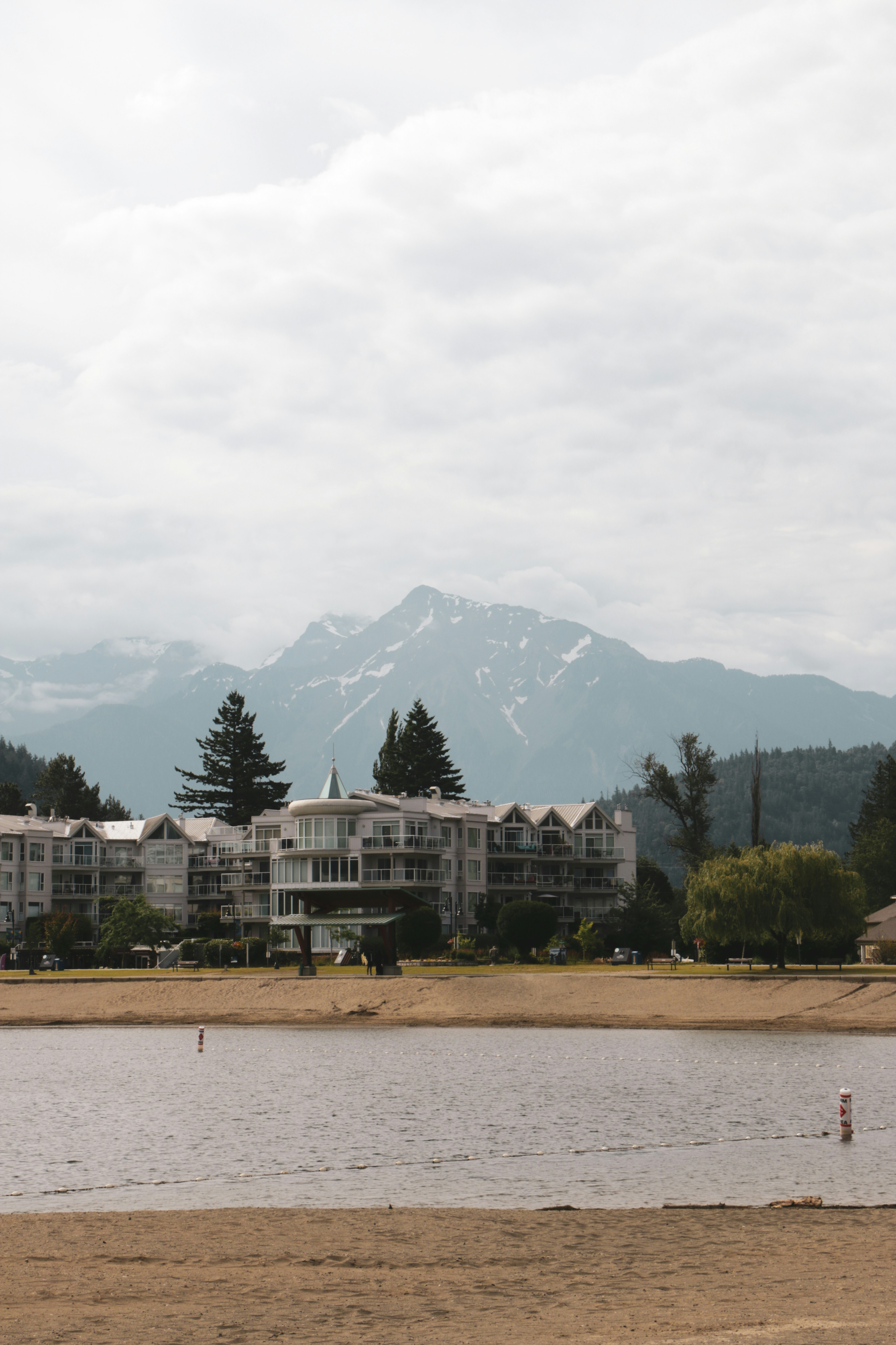 Buildings sit by water with mountains in the background.