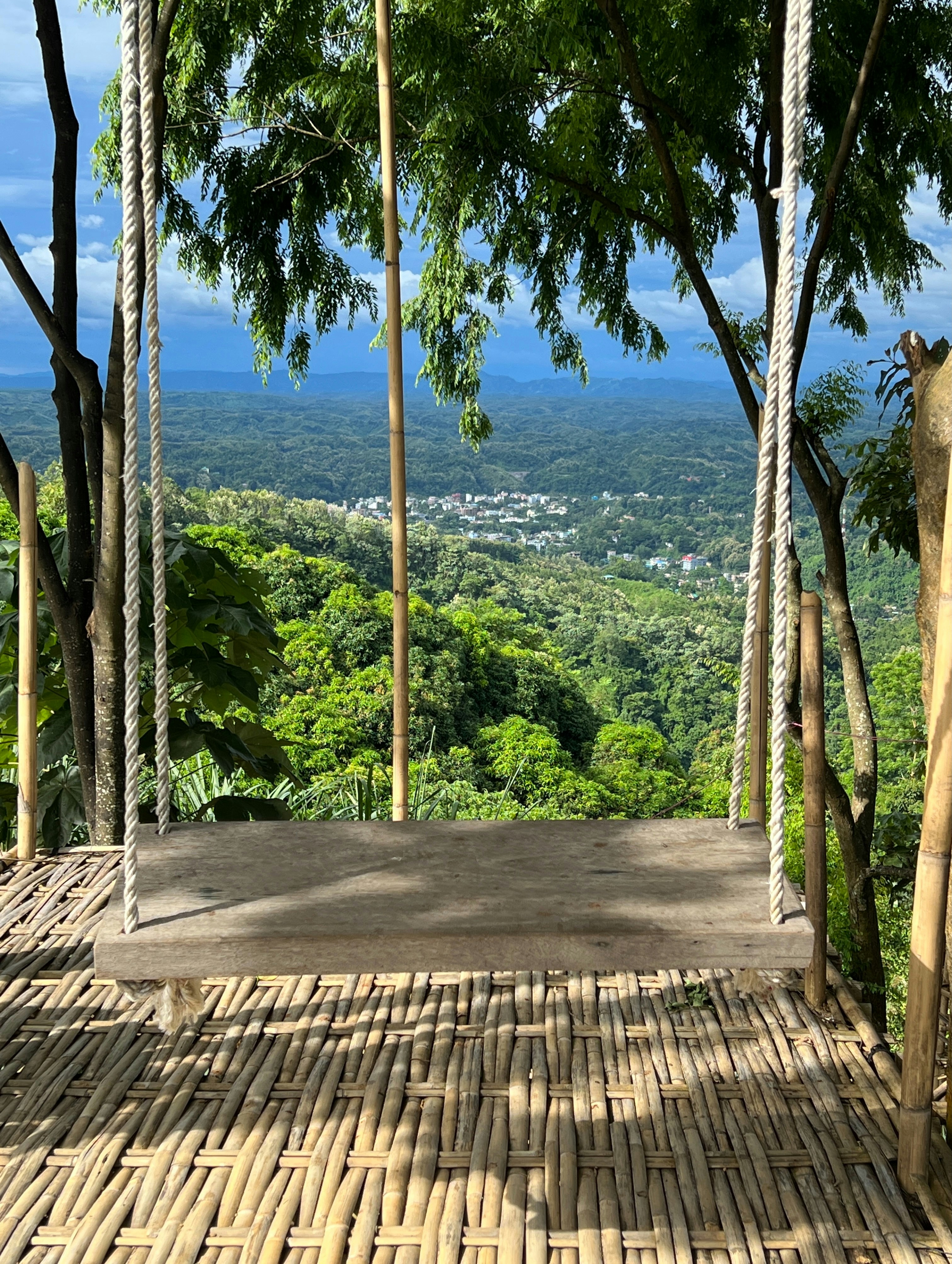 The Hill View from the Cradle | A swing overlooking lush green hills and a town.