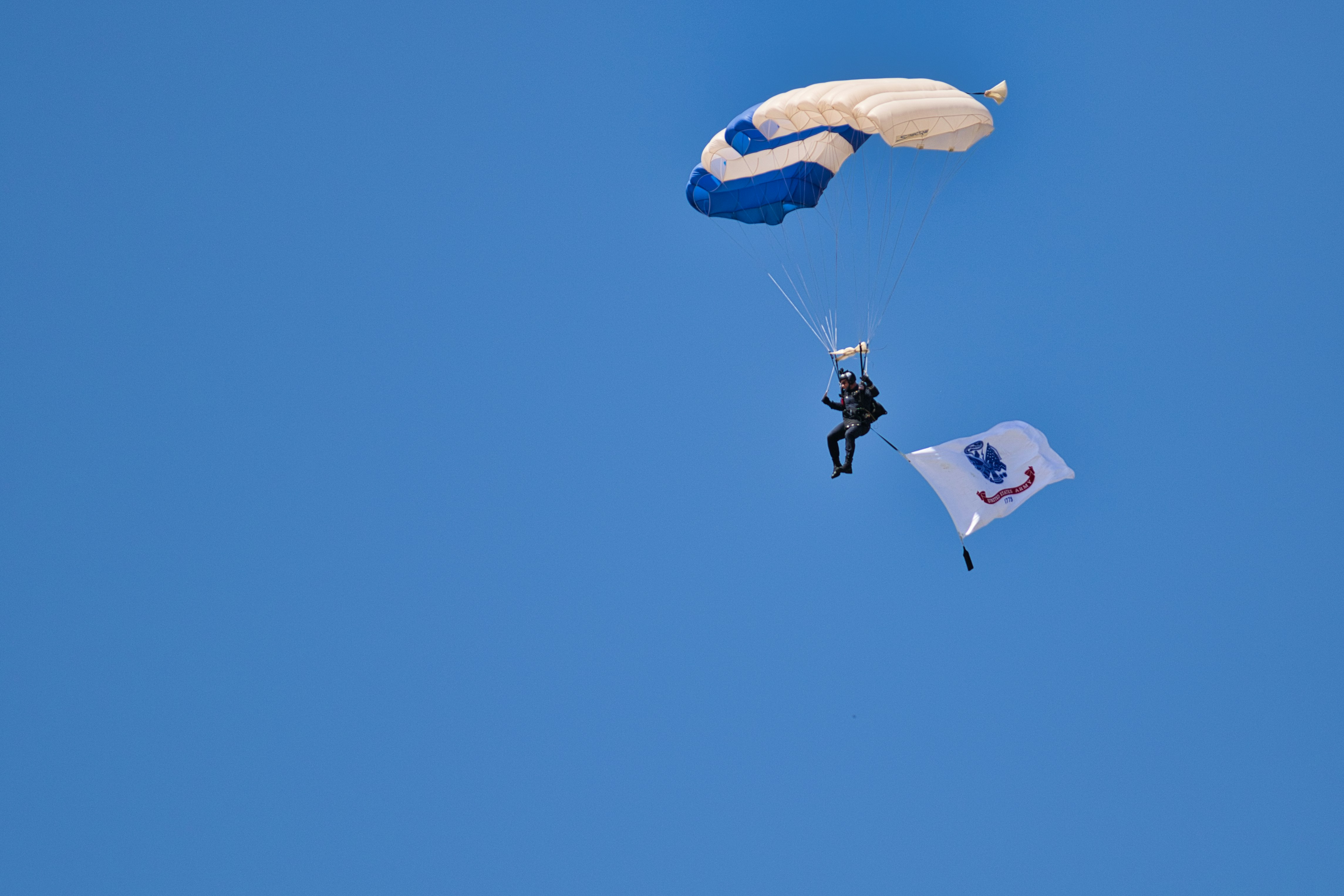 Azure Convergence: Skydiver Navigates Dual Canopies Across a Pristine Sky