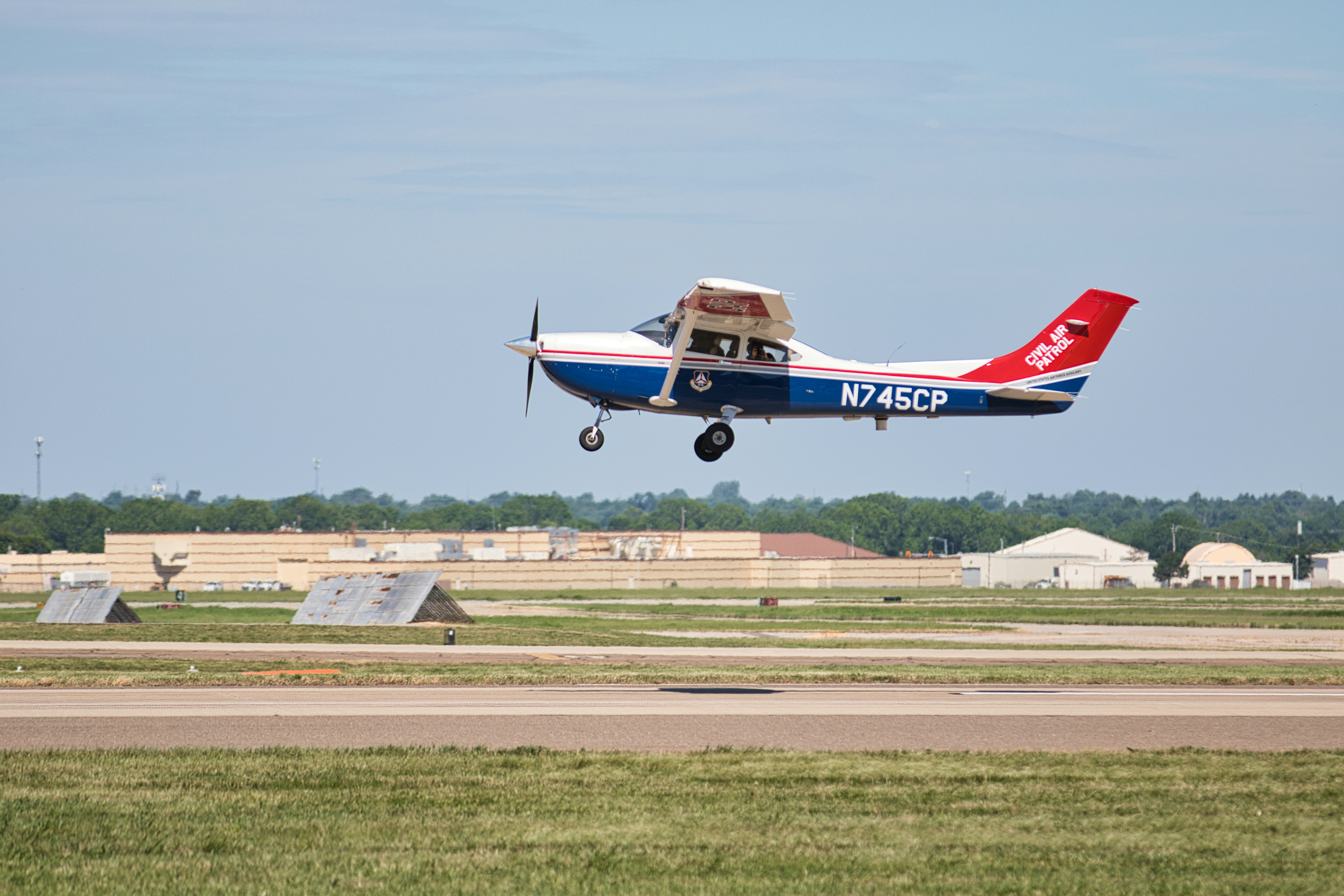 Blue-and-White Cessna Takes Flight Over a Grass Airfield