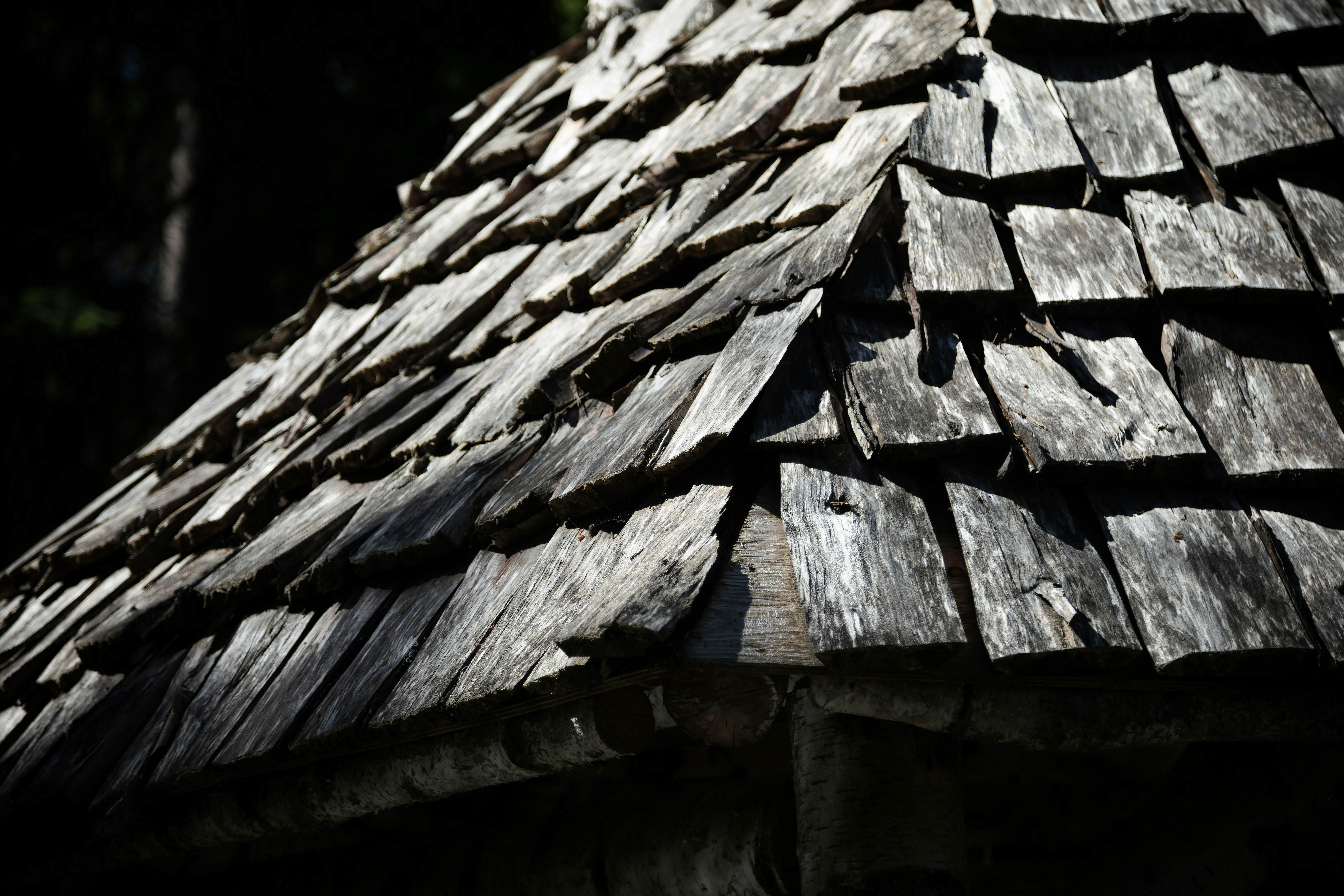 Close-up of a rustic wooden roof with weathered shingles, showcasing the intricate textures and natural aging of the materials.