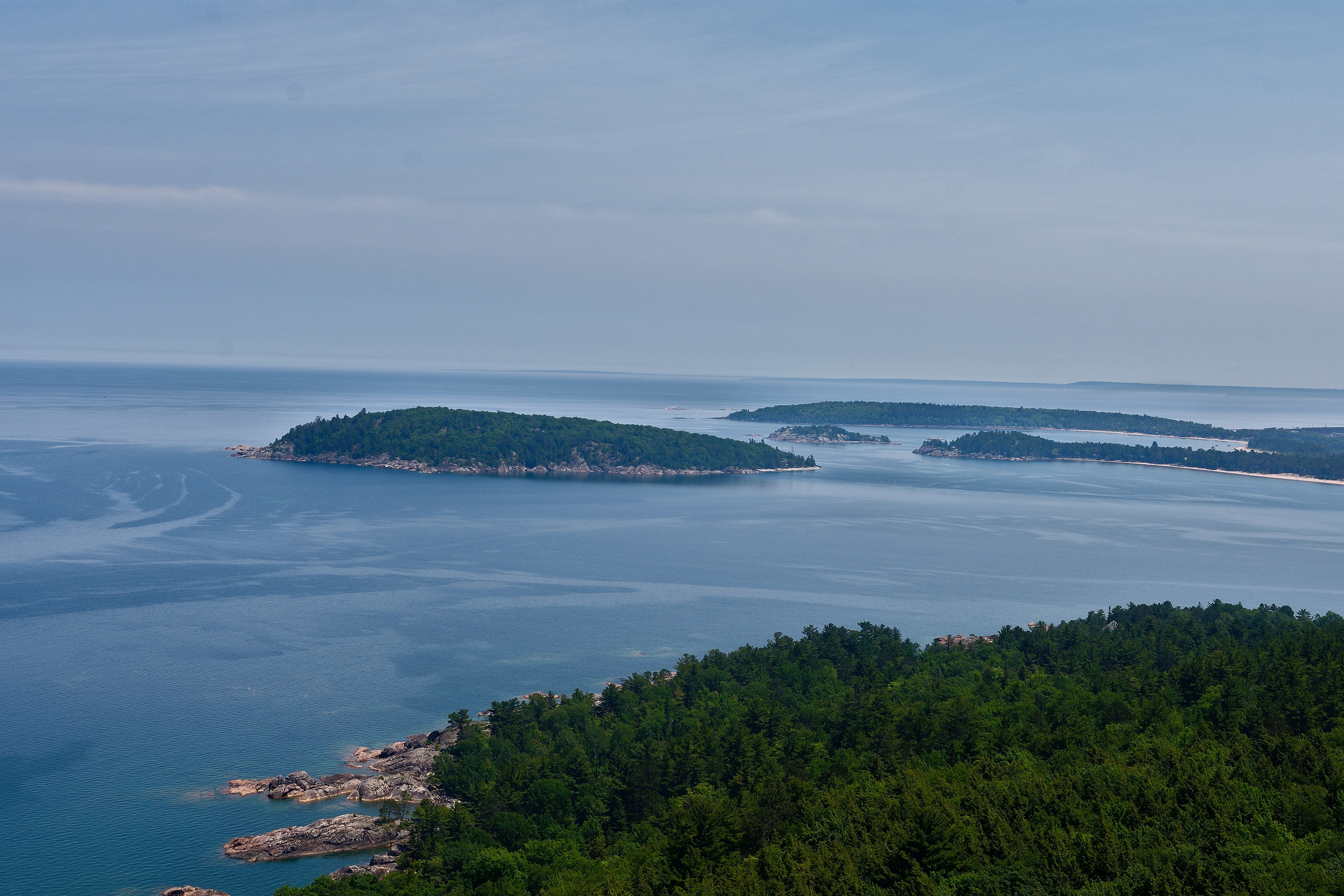 Expansive view of lush green islands surrounded by calm blue waters under a clear sky.