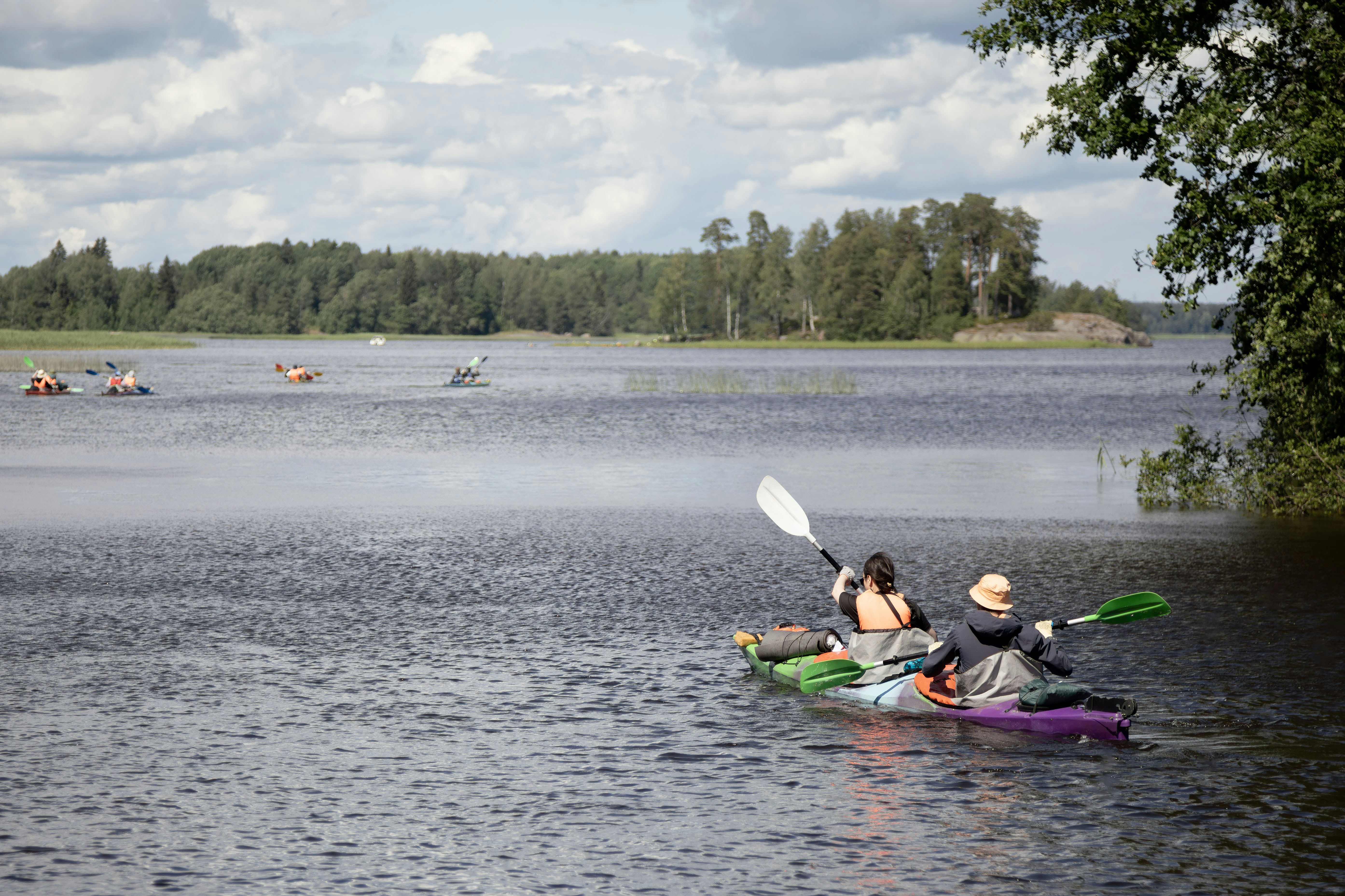 Paddlers in a Quiet River: Duo in a Green Kayak Lead the Fold