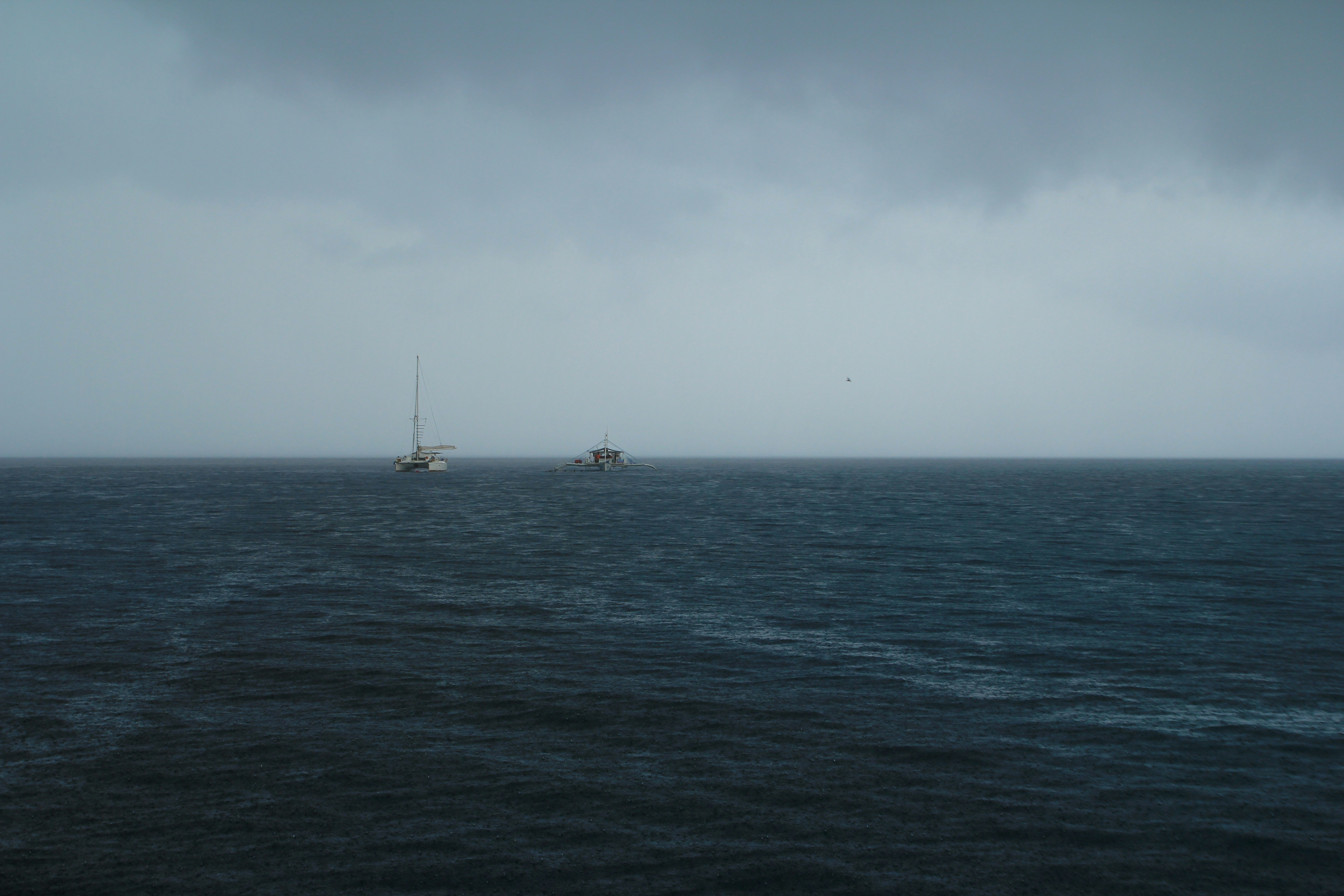 깔랑가만섬 뒤로 비오는 중 | Dark, stormy sea with two boats.