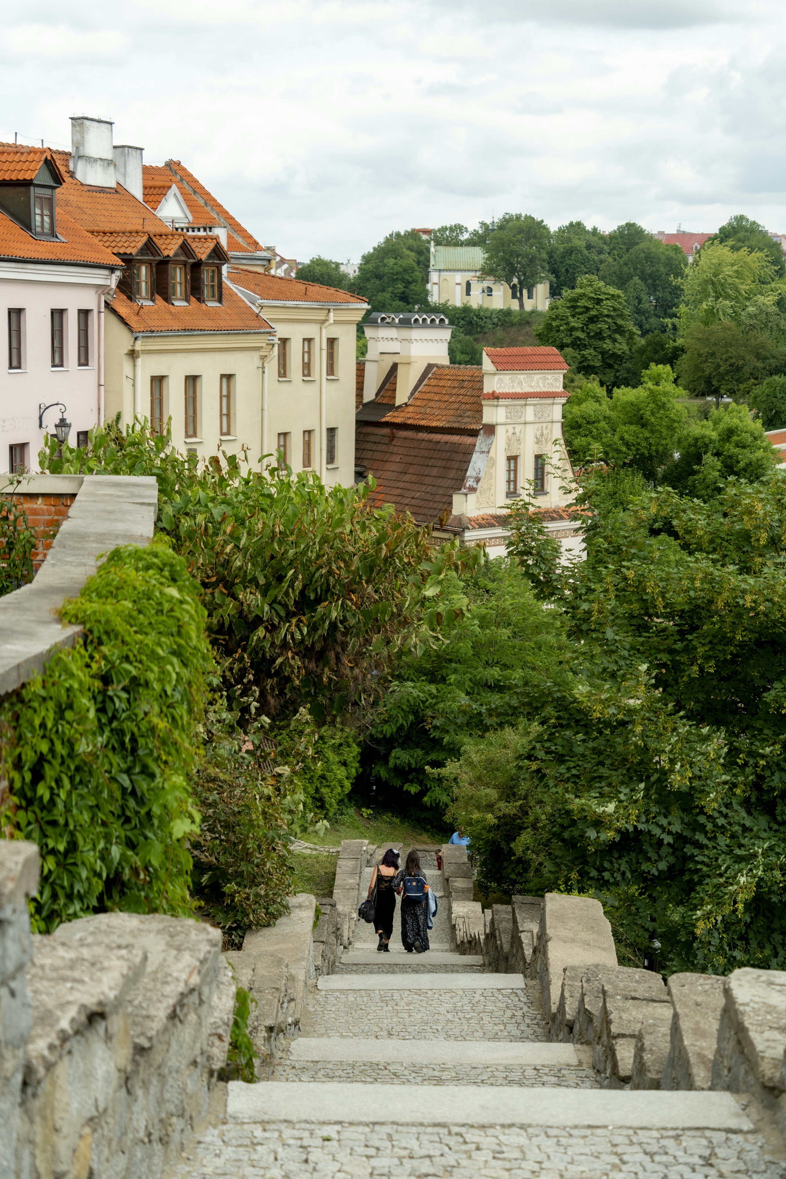 People walk down stone stairs in a european town.