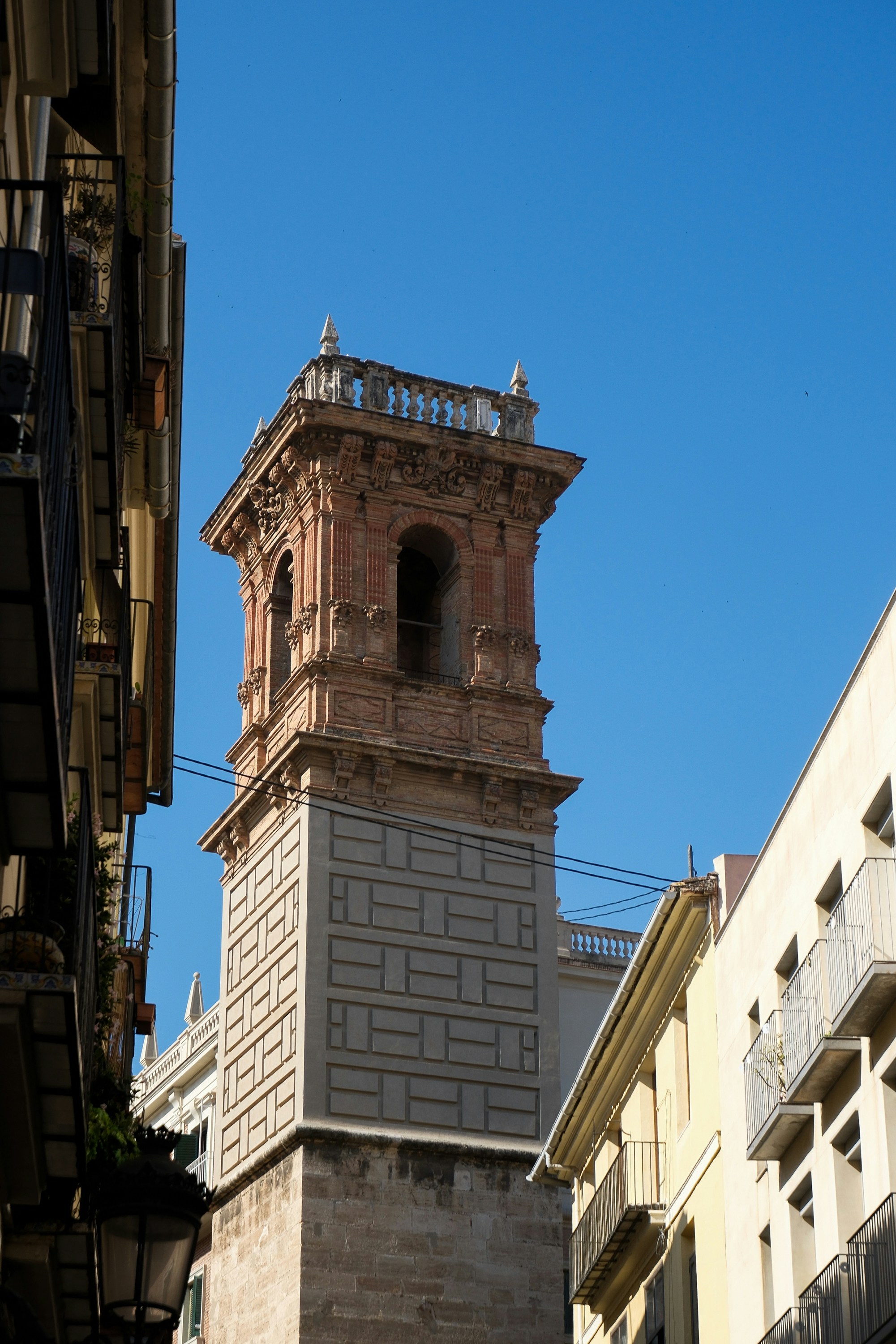 A brick tower stands between buildings.