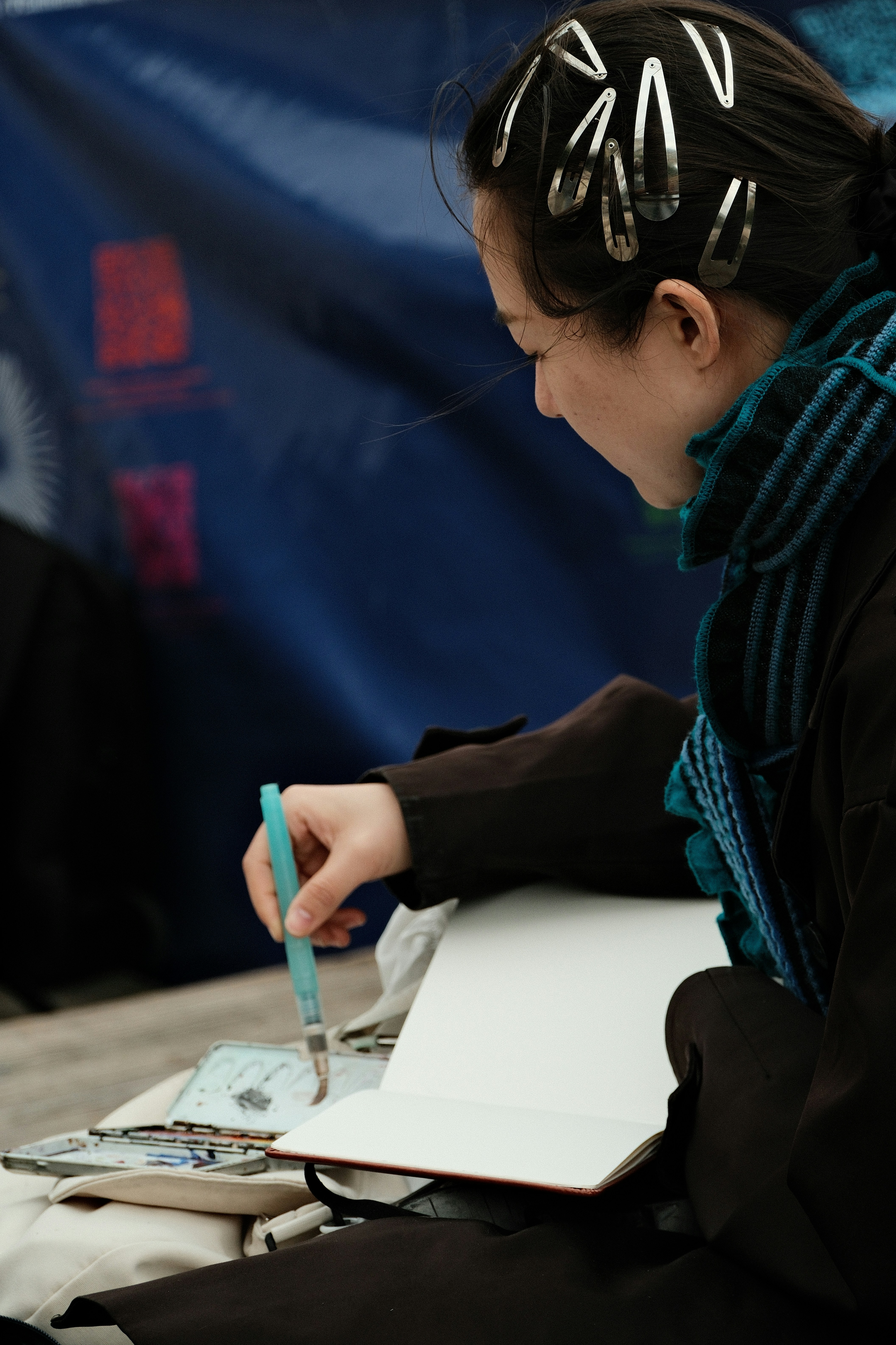 A woman sketches with a pen in her notebook.