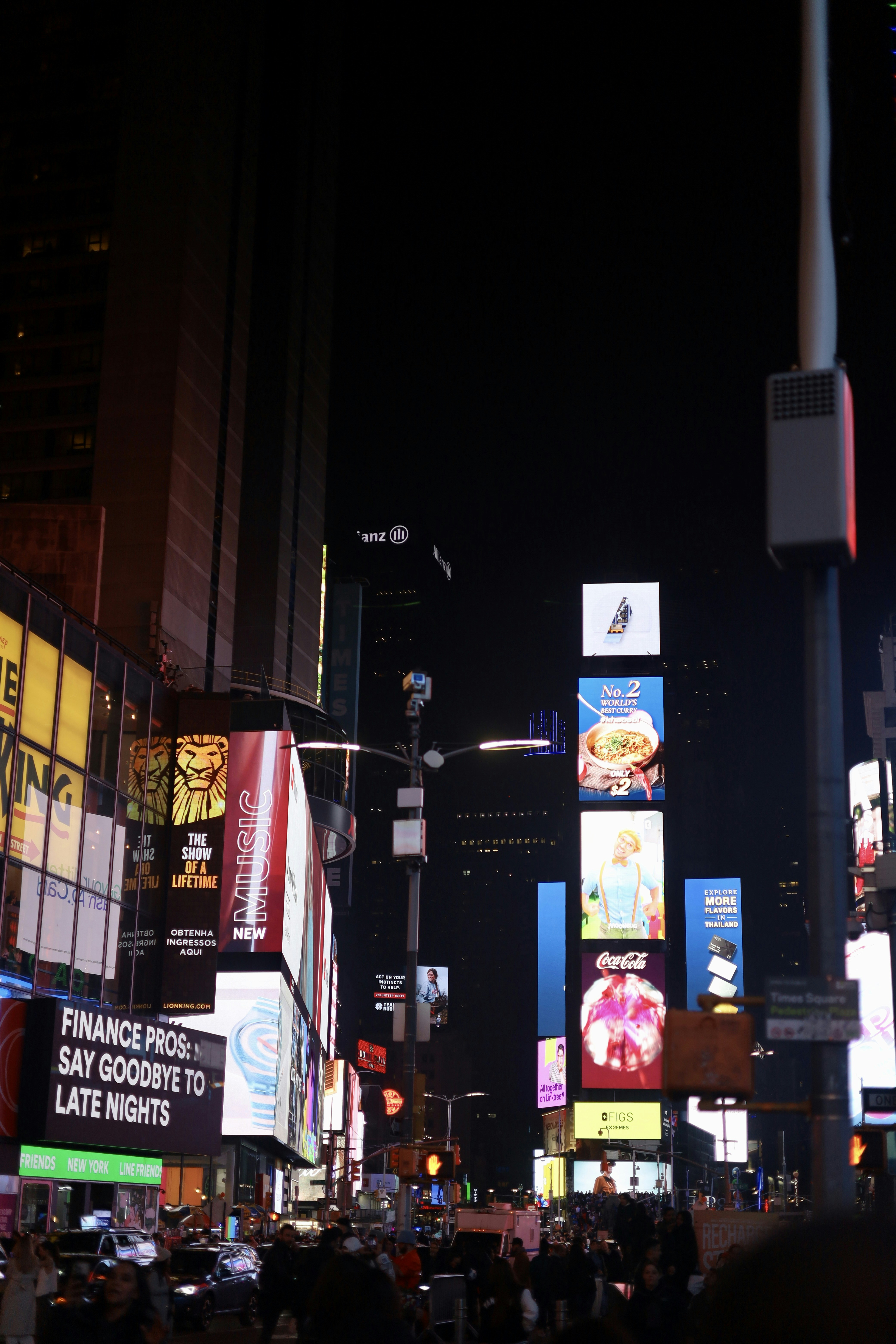 Vibrant billboards illuminate the bustling streets of Times Square at night, showcasing a blend of advertisements and city life.